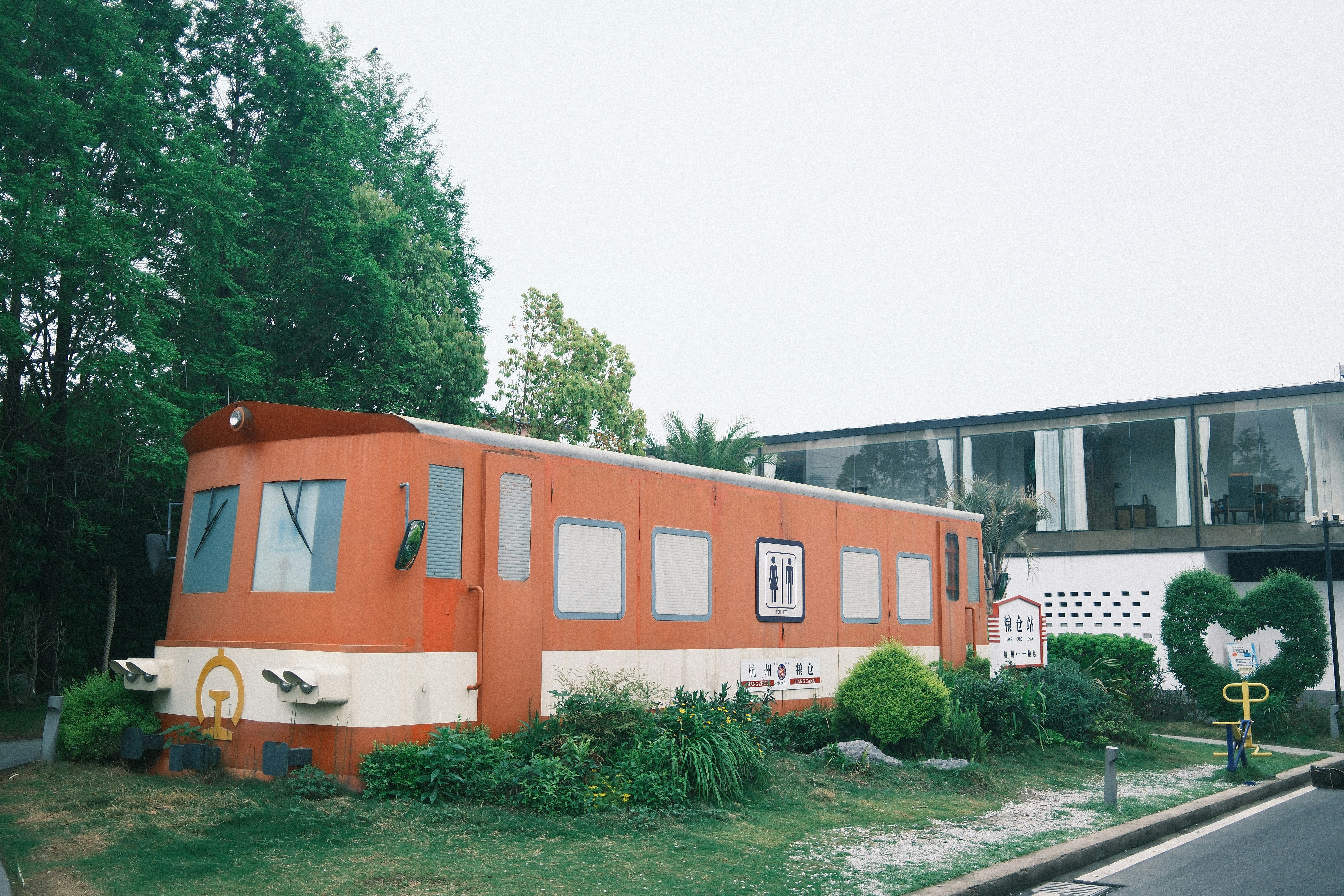 Restored orange railcar guarding a garden landscape
