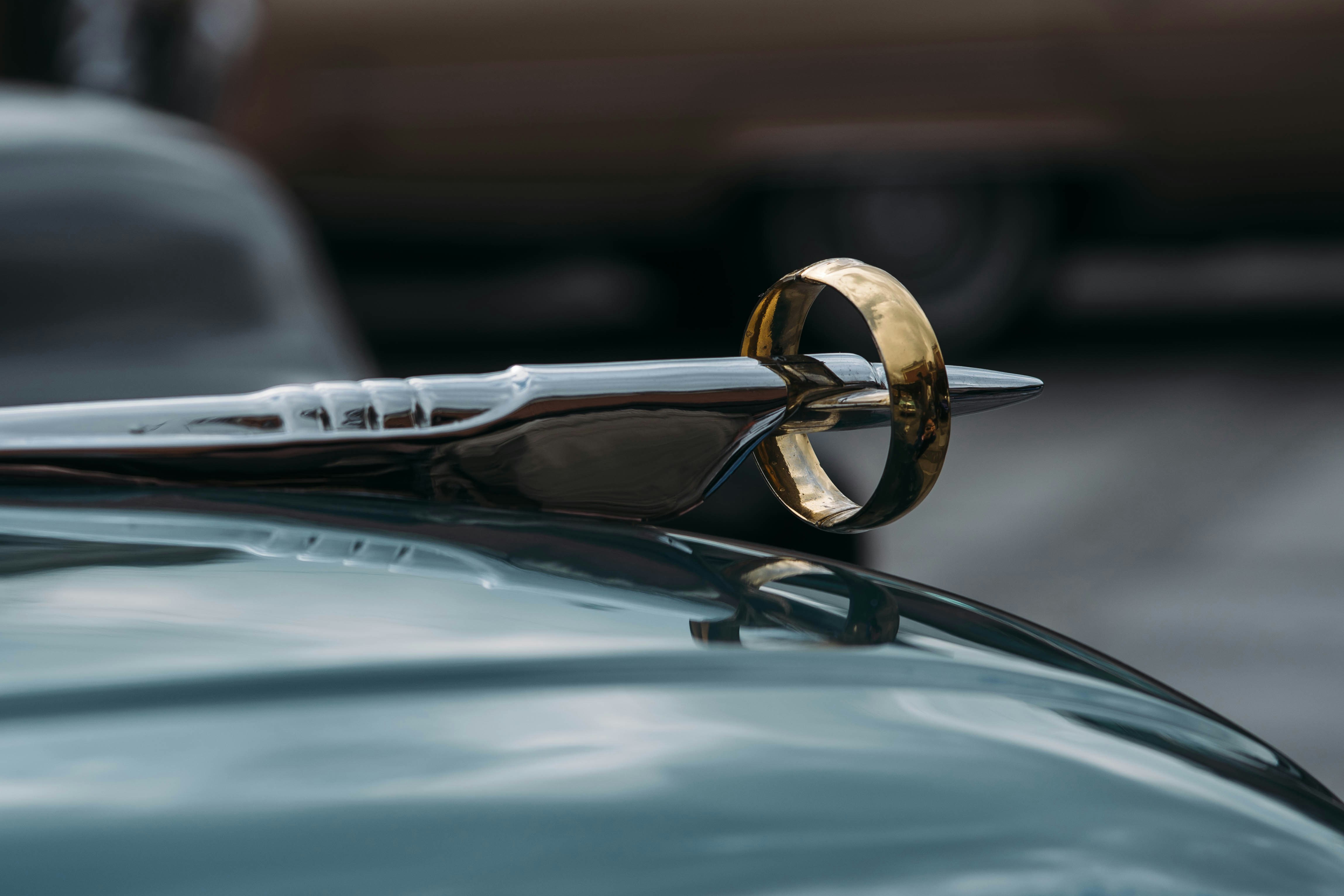 Golden ring on a chrome spear: a vintage car hood ornament in sharp focus