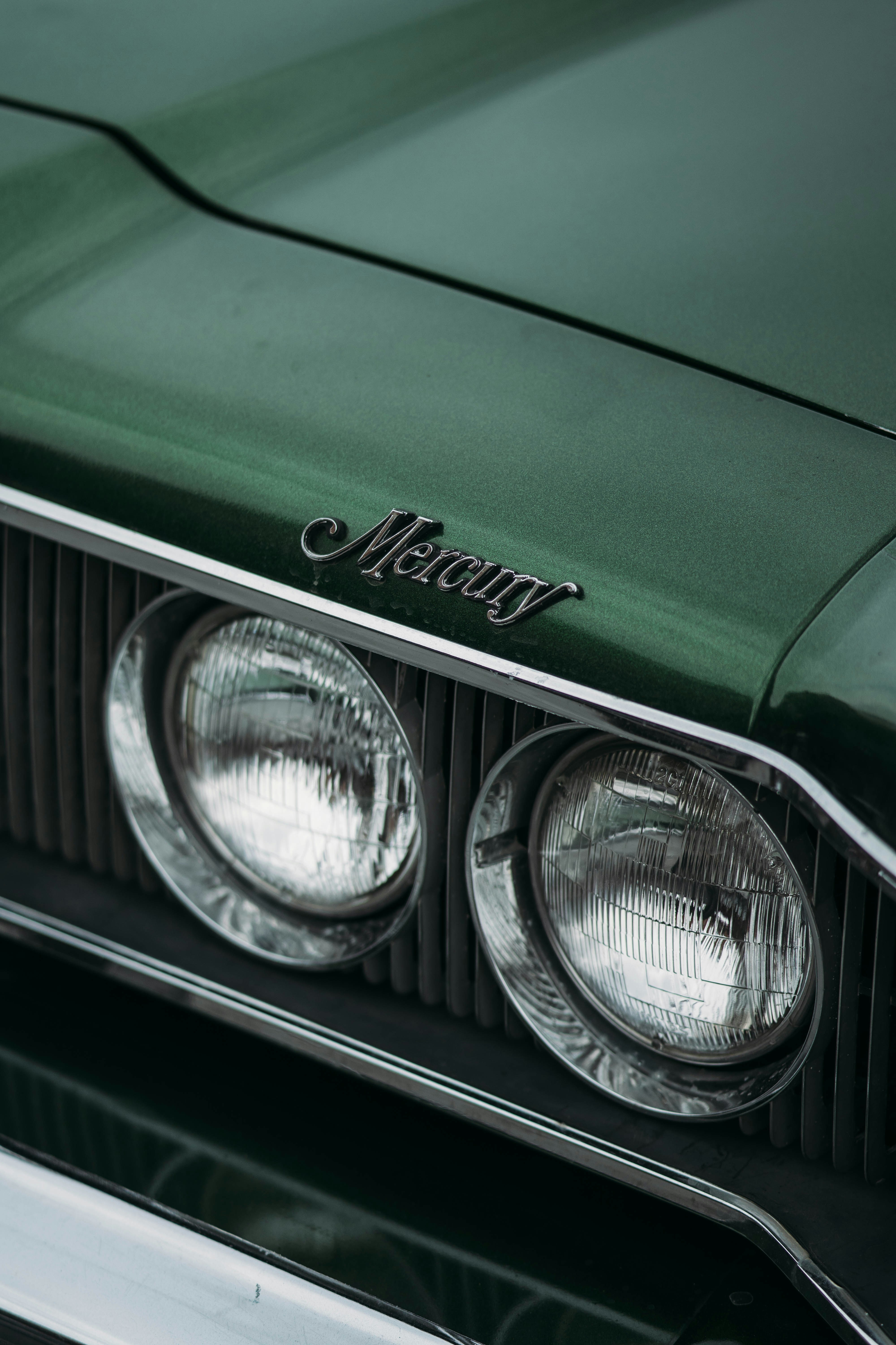 Verdant classic: Mercury badge and dual headlamps on a vintage green automobile