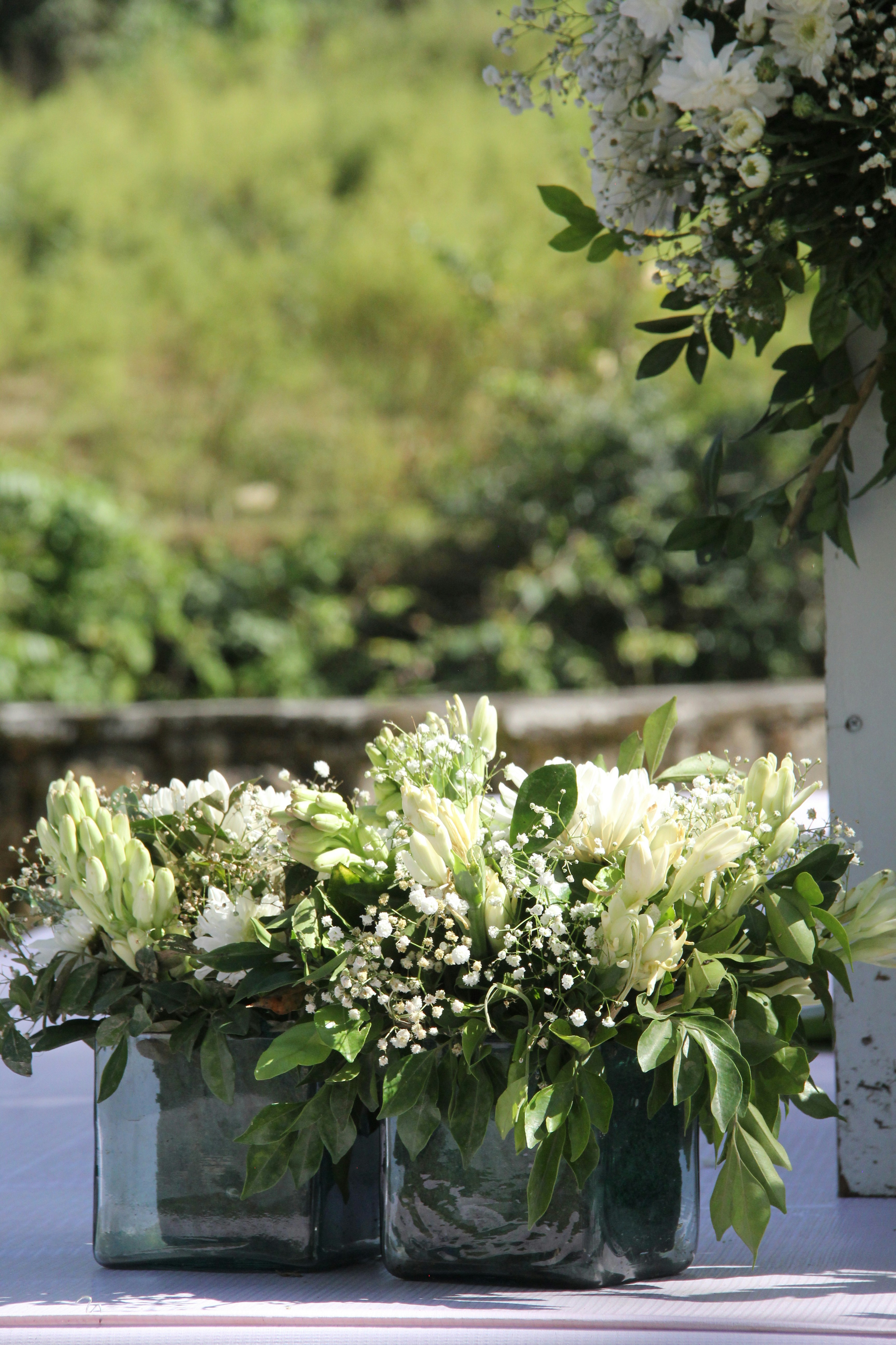 Bouquet Corner: White Florals in Glass Vases Framing a Rustic Ceremony