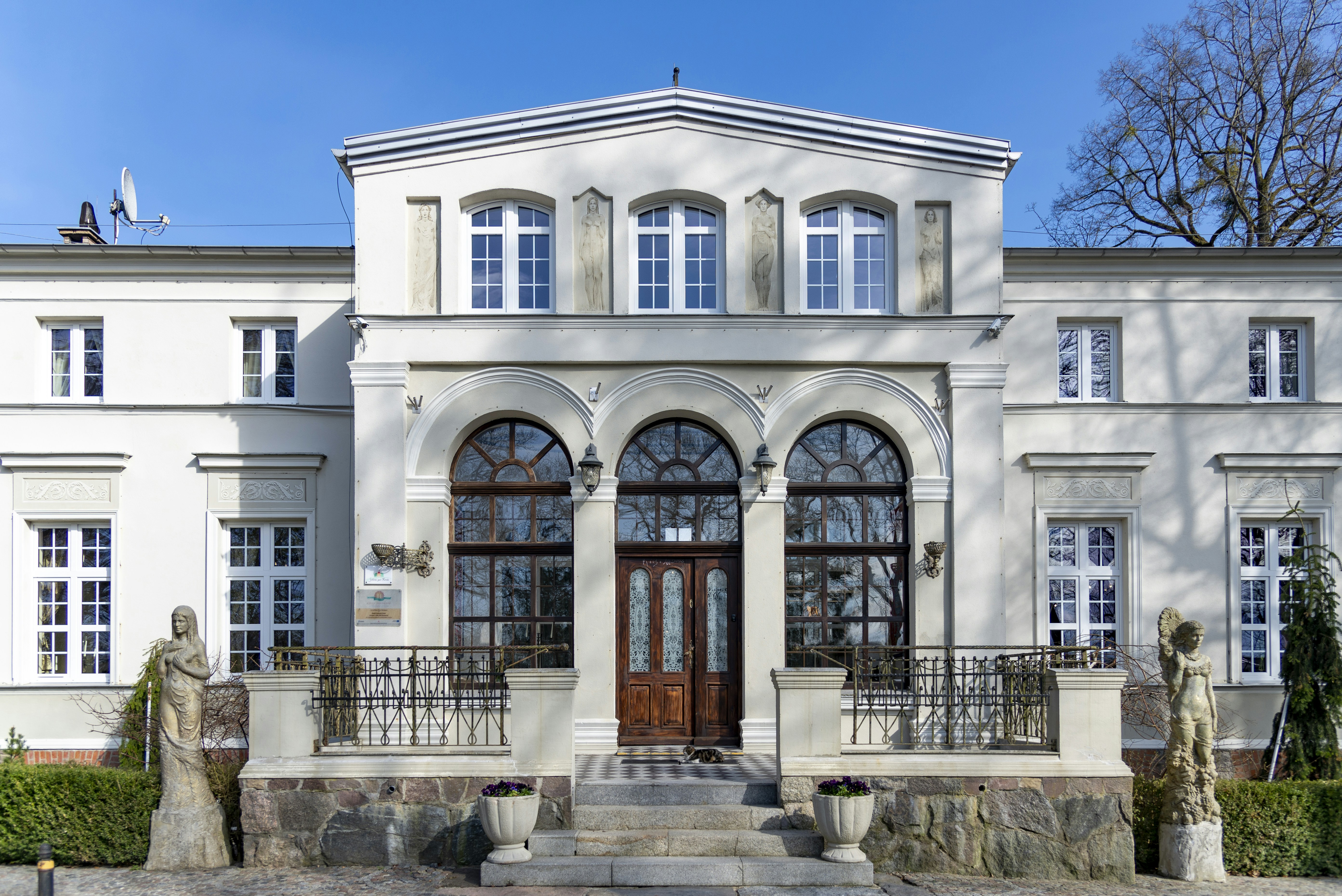 Grand Villa Facade: Symmetry, Arches, and Statues Framing a Central Doorway