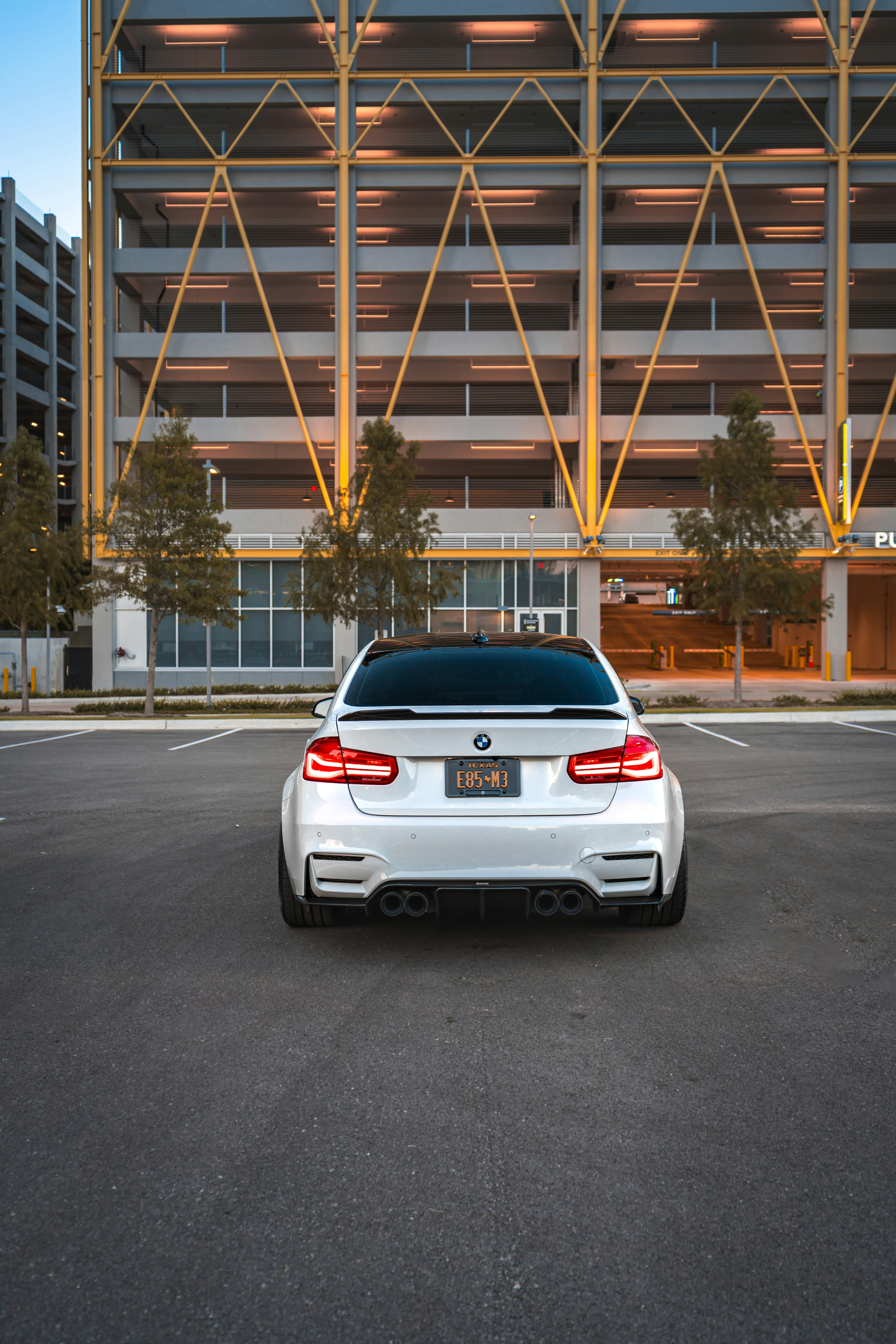 Rear View: White BMW in a Quiet Parking Lot Framed by an Architectural Skeleton
