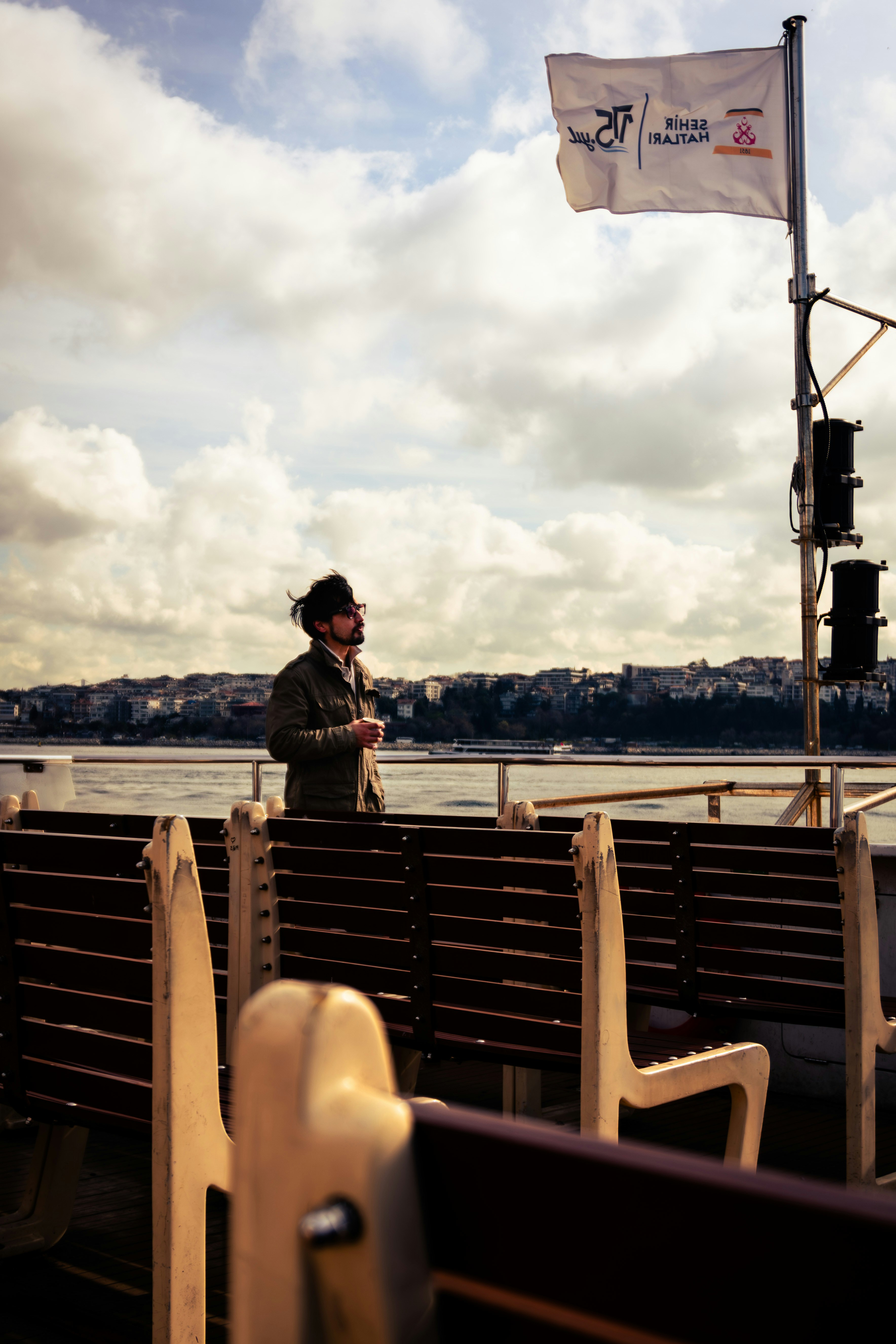 A solitary figure on a riverside deck under a drifting flag