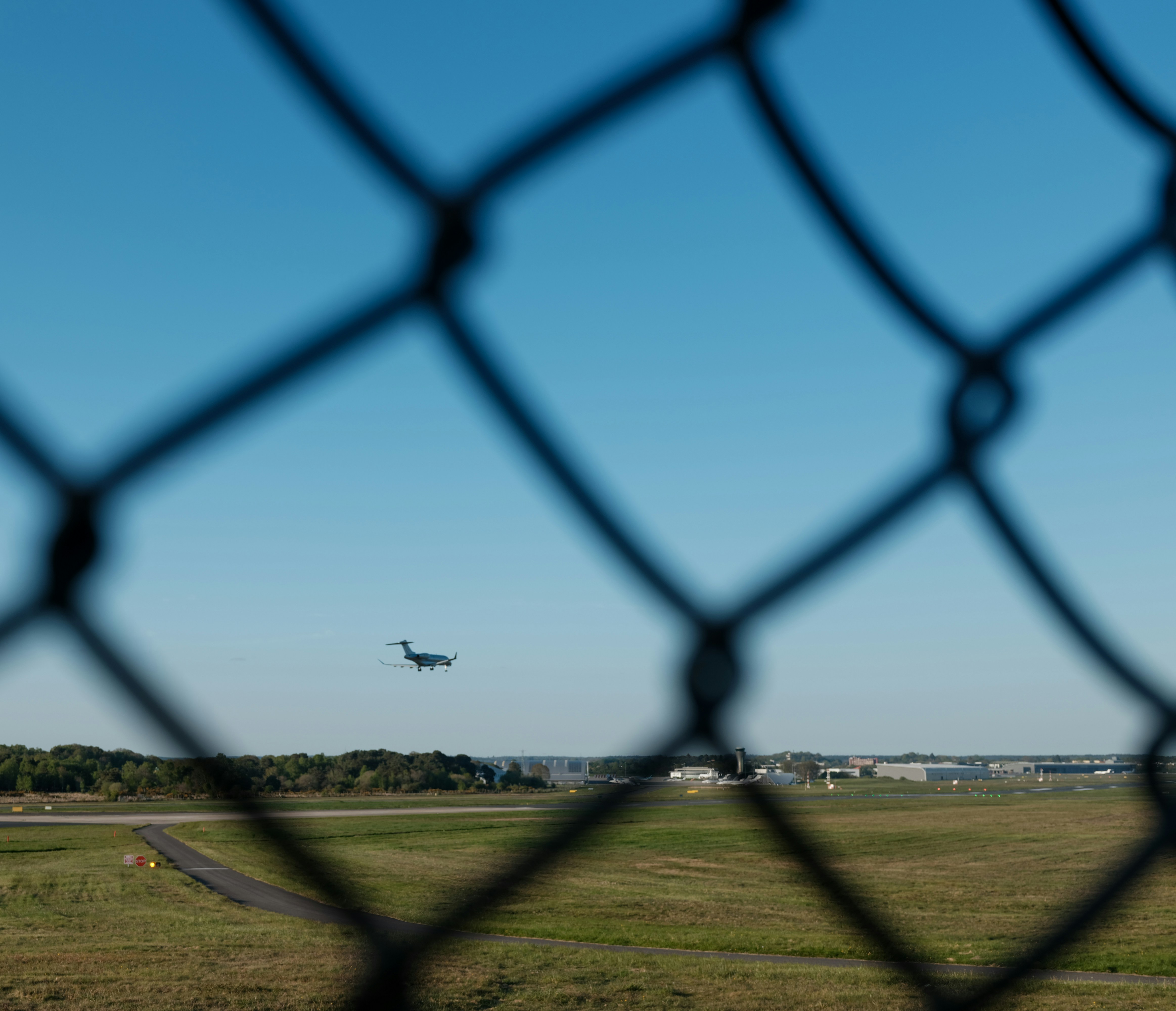 Drone Emergence over a Field Framed by Chain-Link