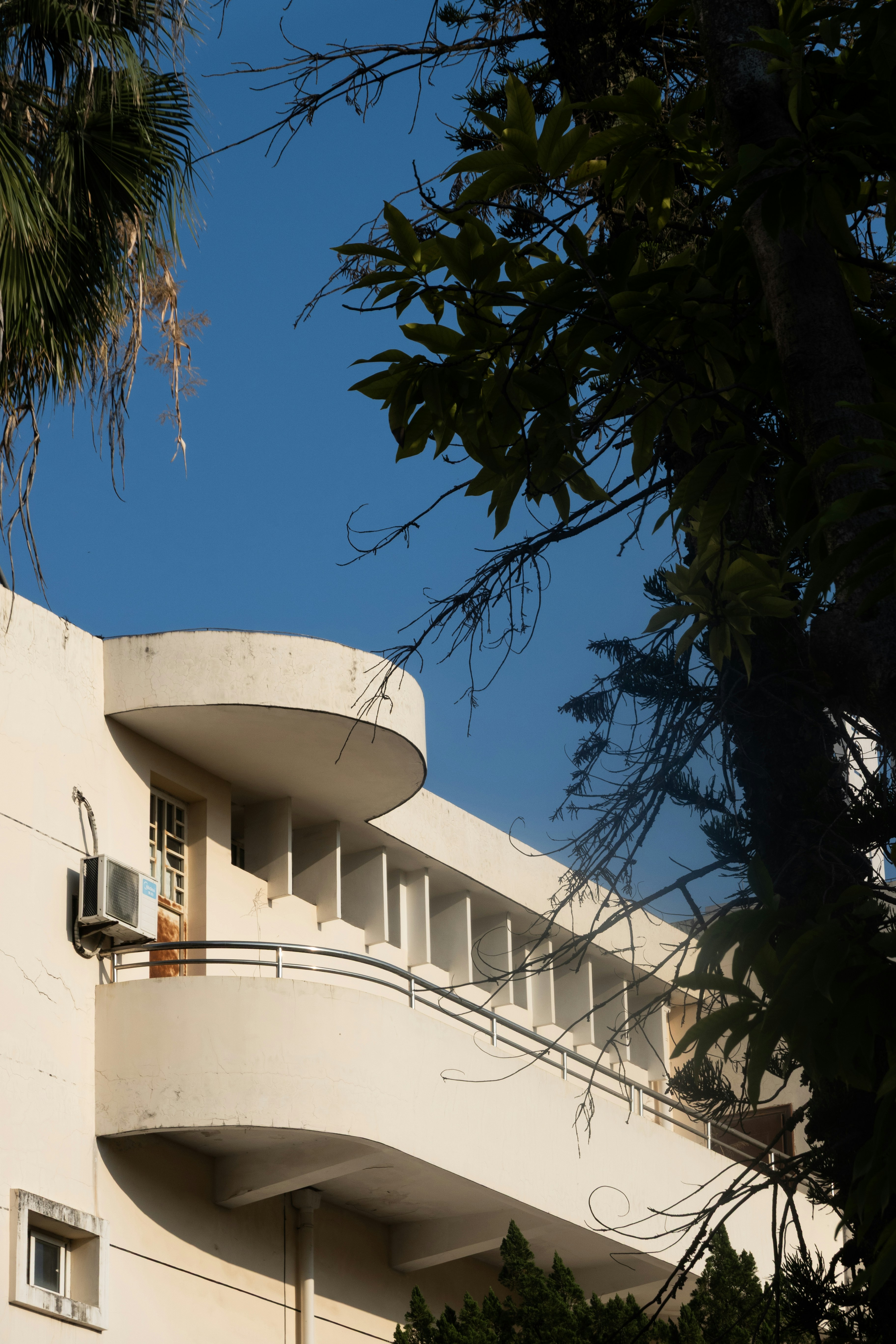 Curved Balcony Echoes: A Sunlit White Facade Under a Clear Blue Sky