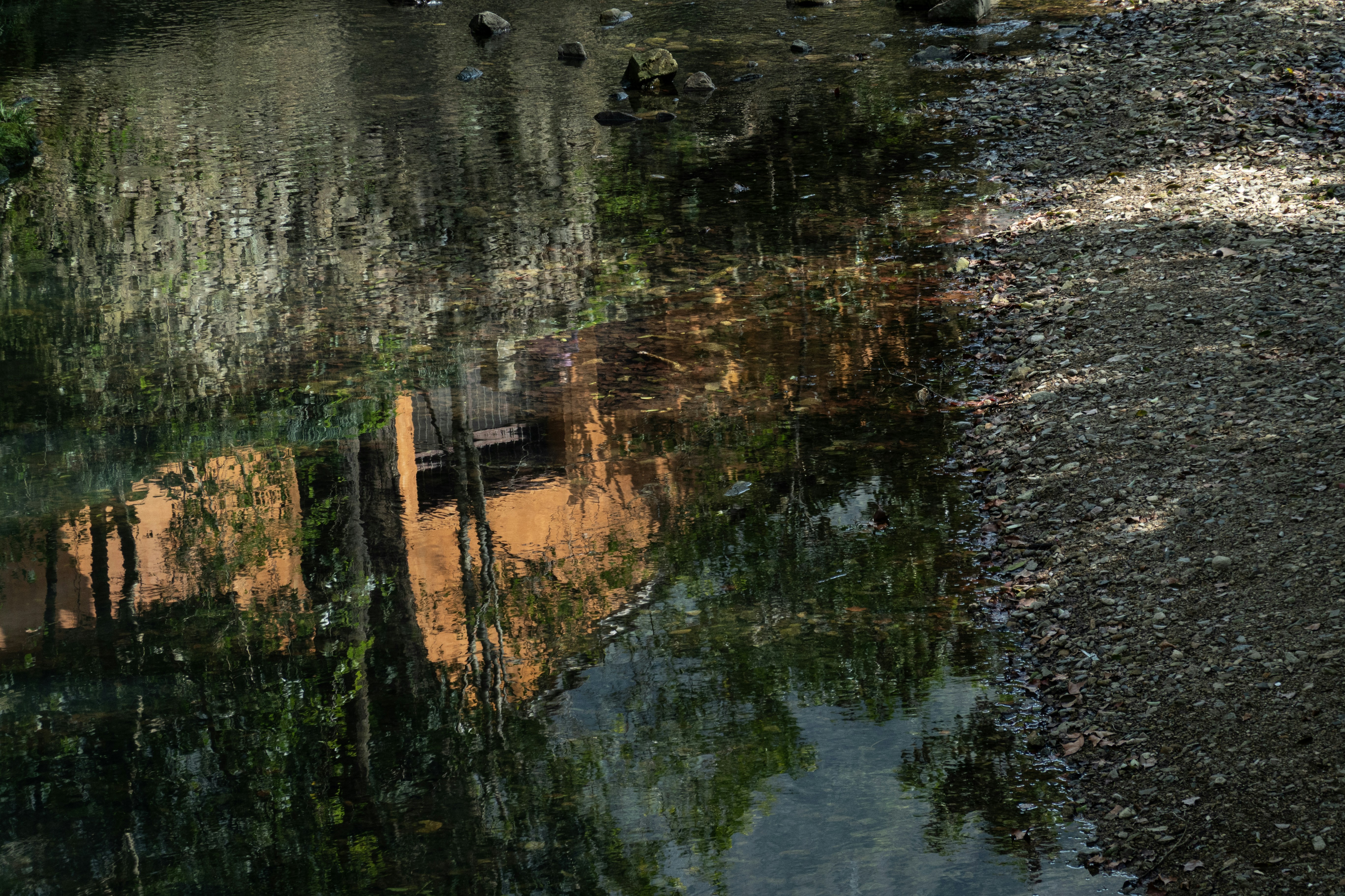 Reflections in a Quiet Creek: Sunset Hues on Pebbled Banks