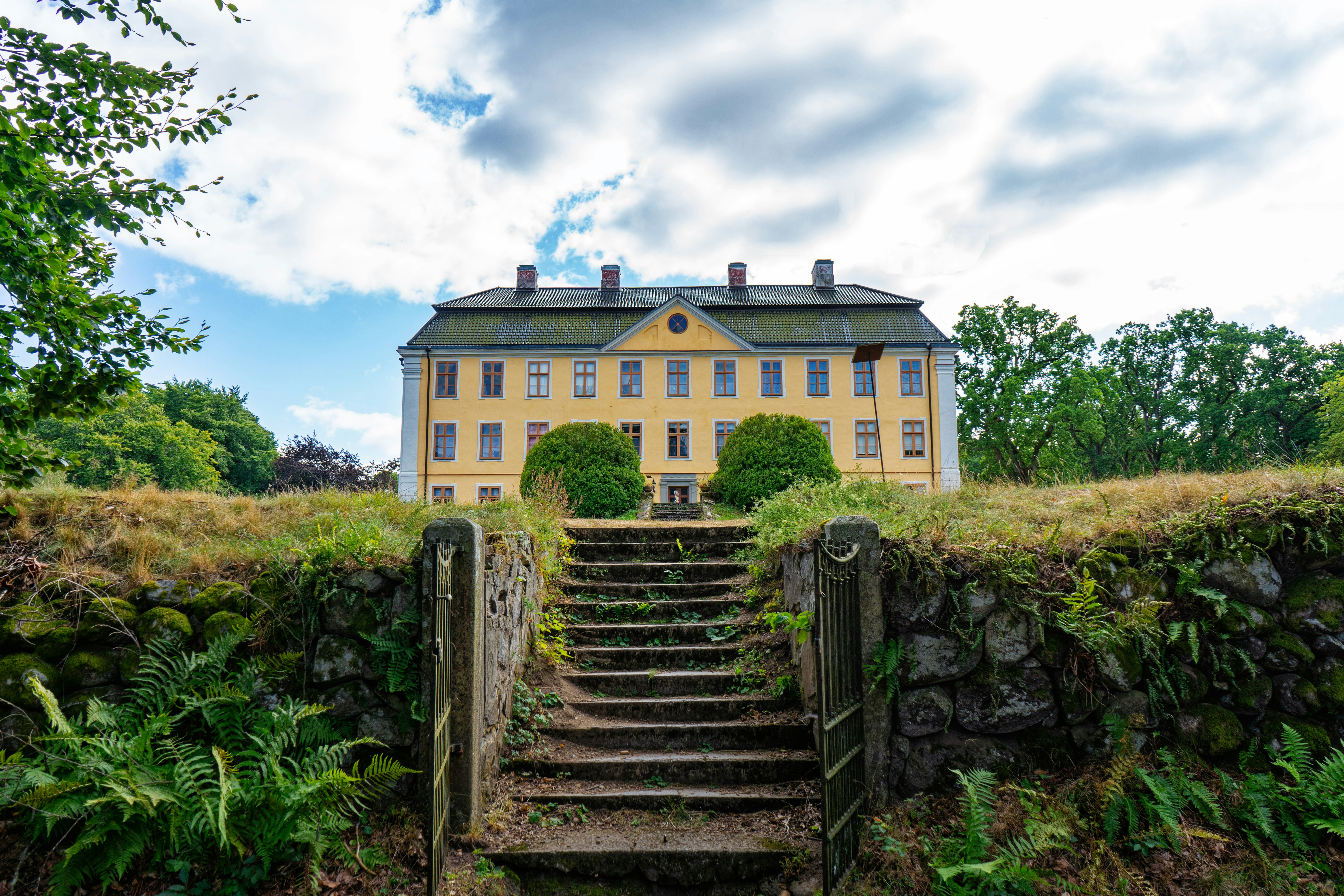 Sunlit manor rises from mossy steps amid verdant banks