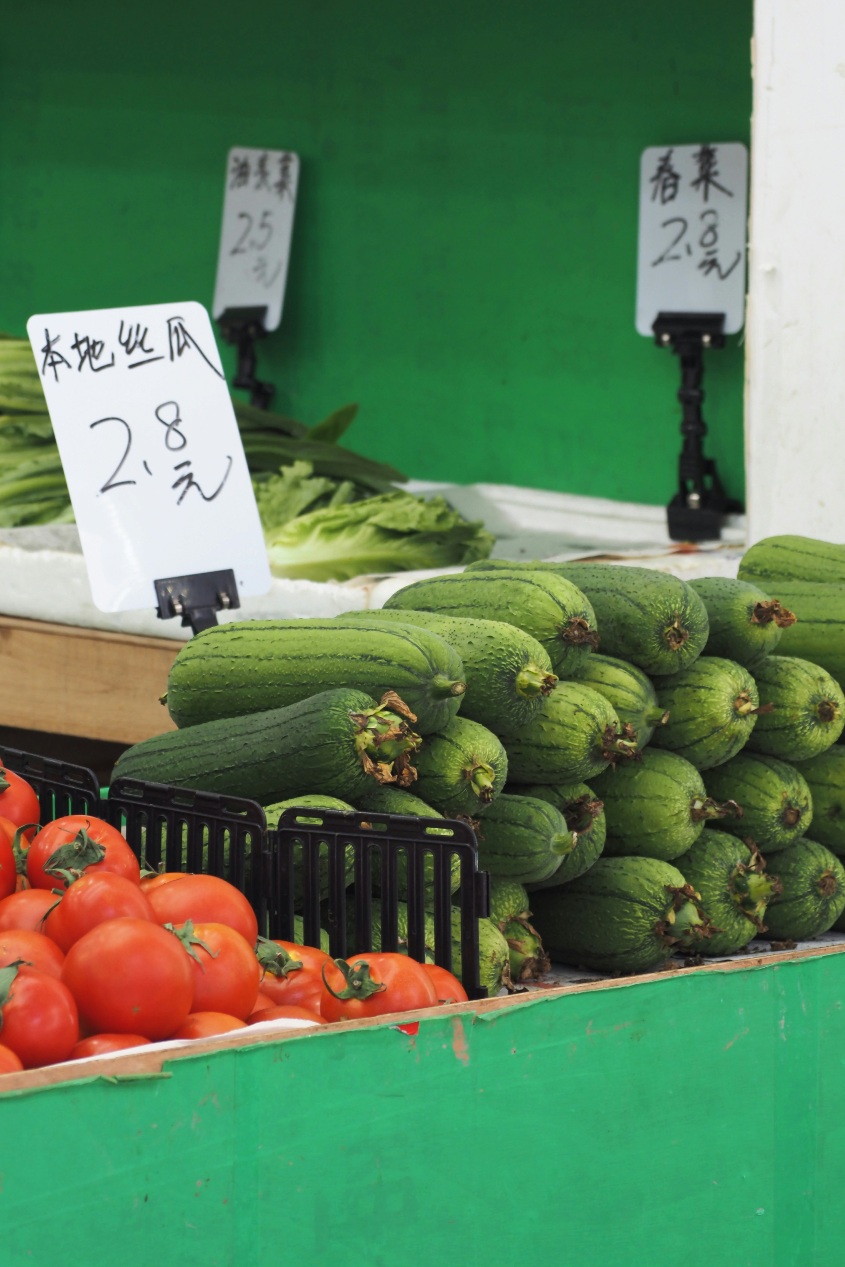 Green cucumbers and red tomatoes at a market stall