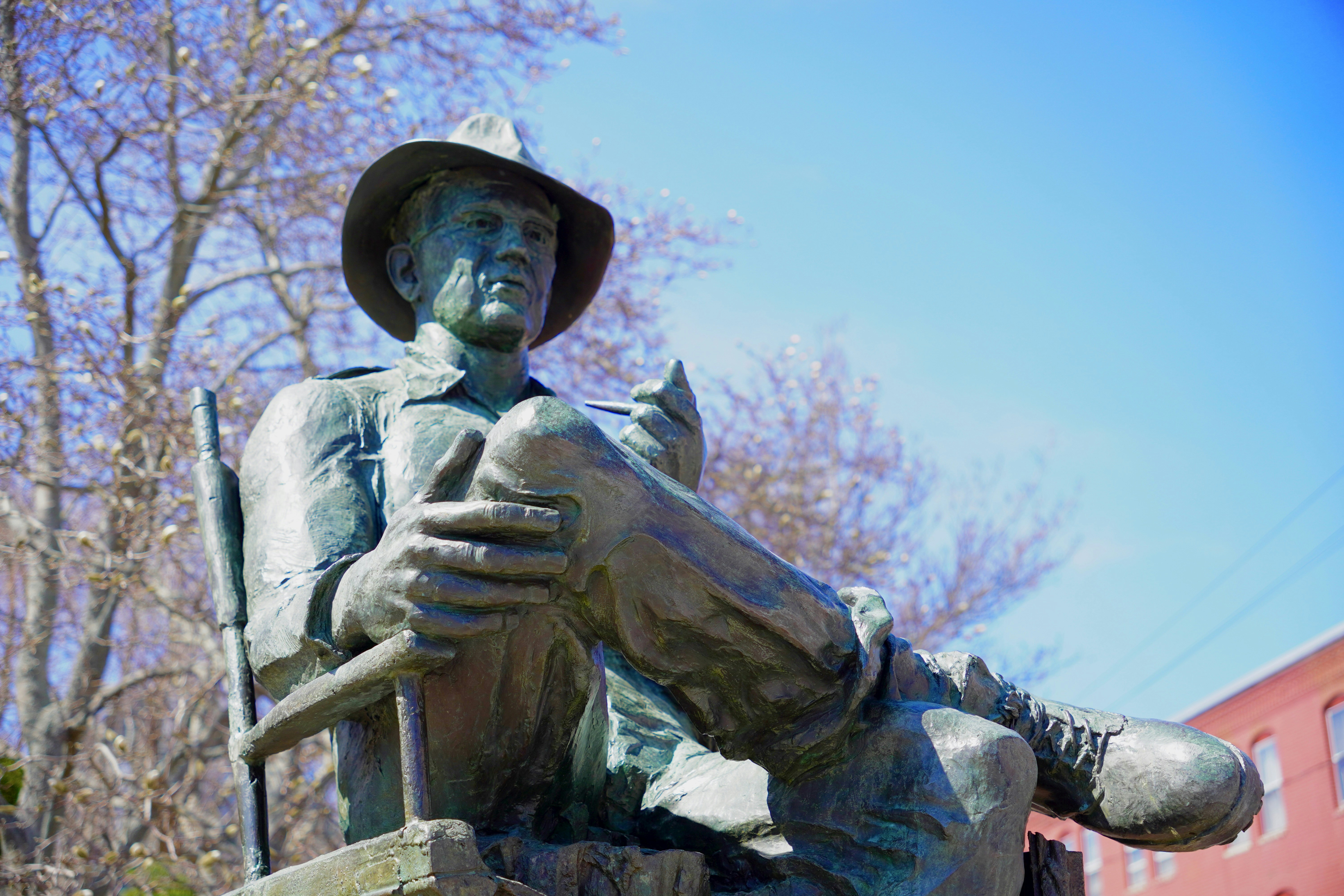 Bronze Cowboys wait on the plaza: a resting figure under spring light
