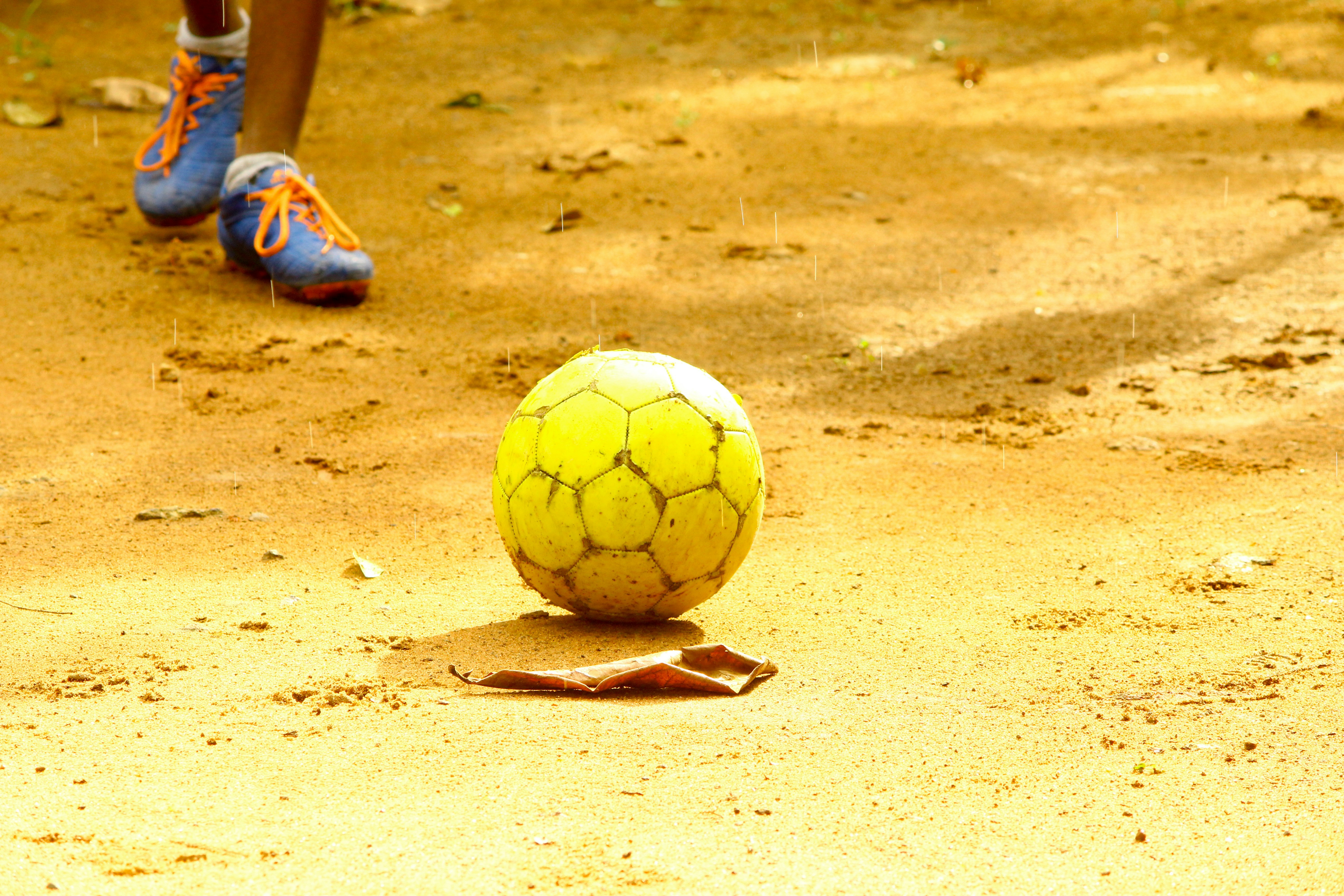 Yellow Ball on Dusty Field: A Moment Before Kick
