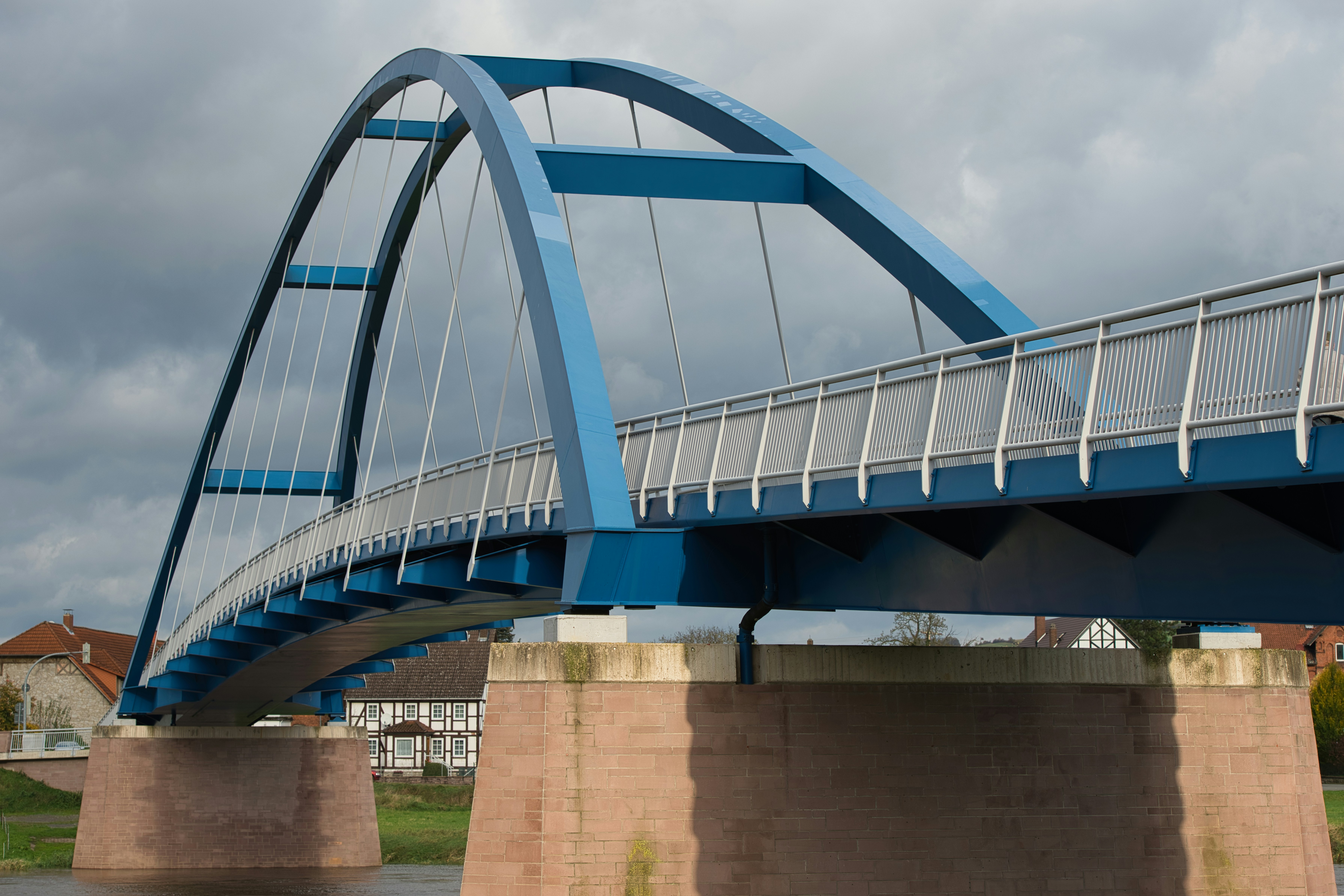 Blue Arch Over the River: A Modern Footbridge in Clear Light