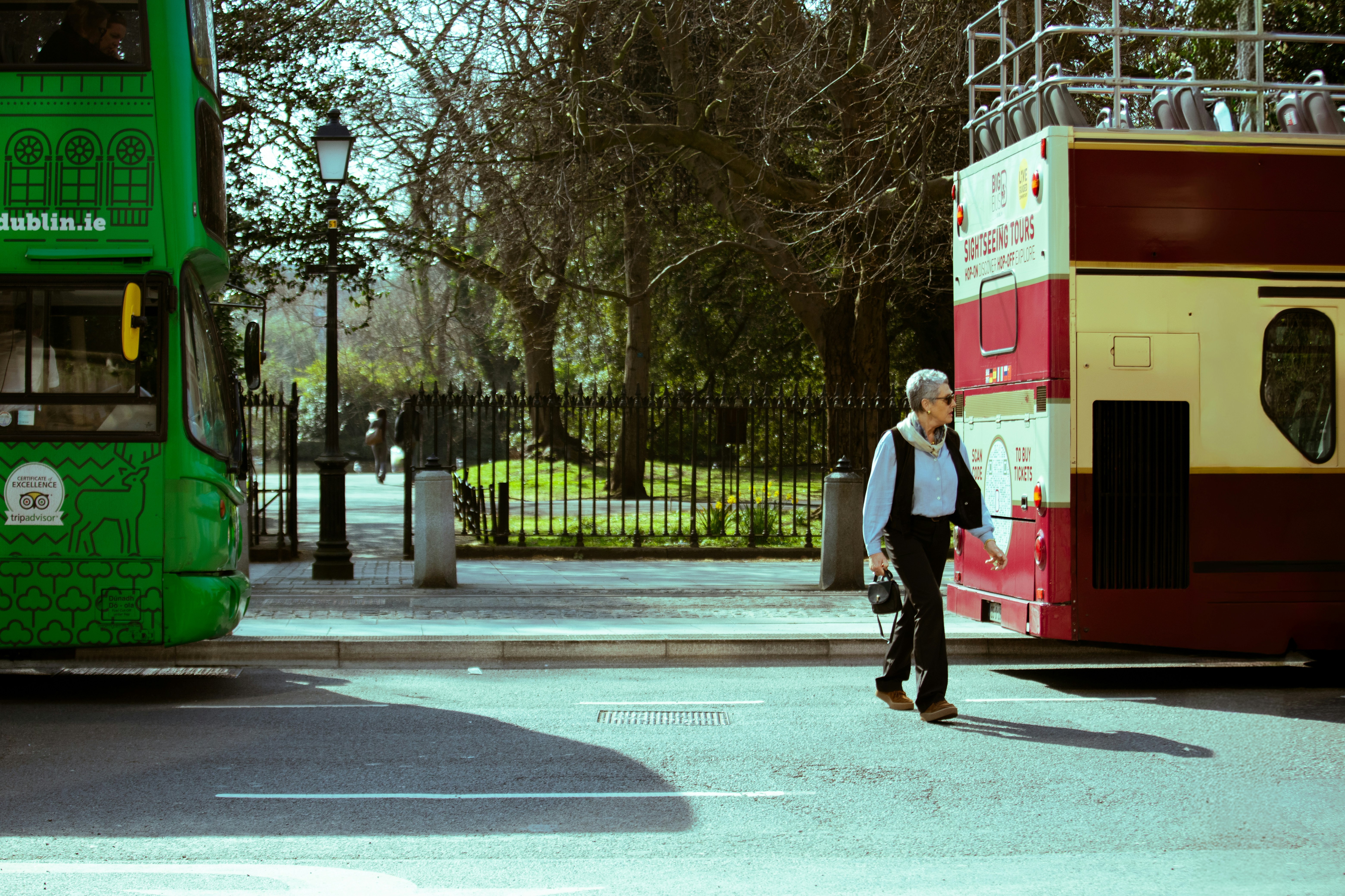 Gliding Pedestrian Between Green and Crimson Carriages in a Bright City Street