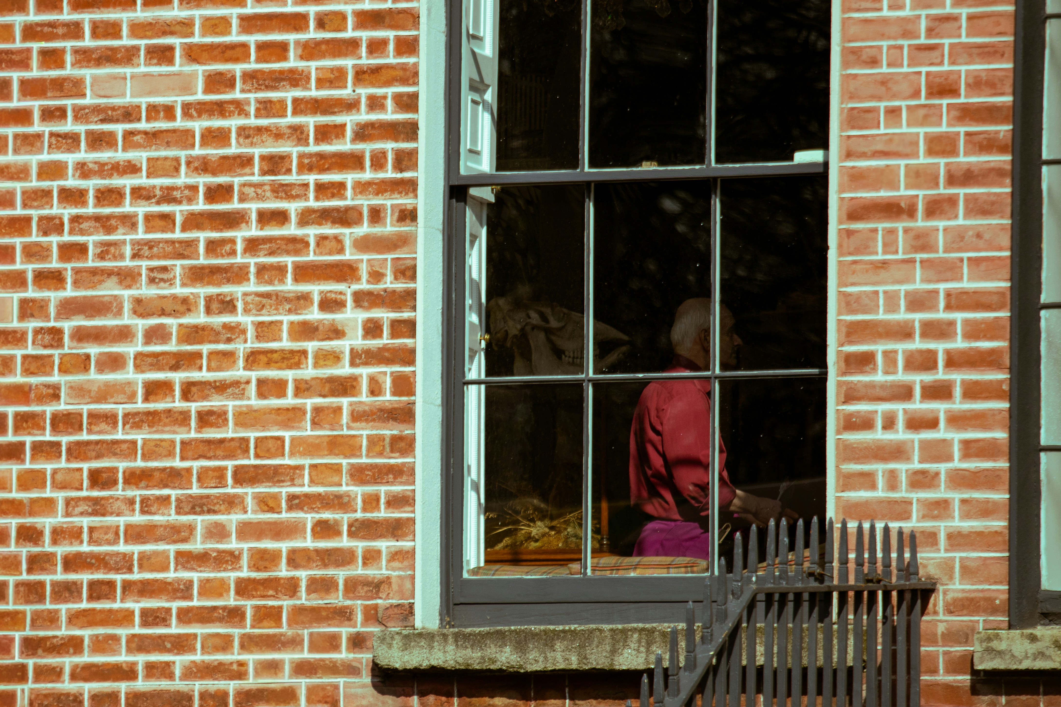 Red-clad Figure in a Window: A Quiet Brick Portrait