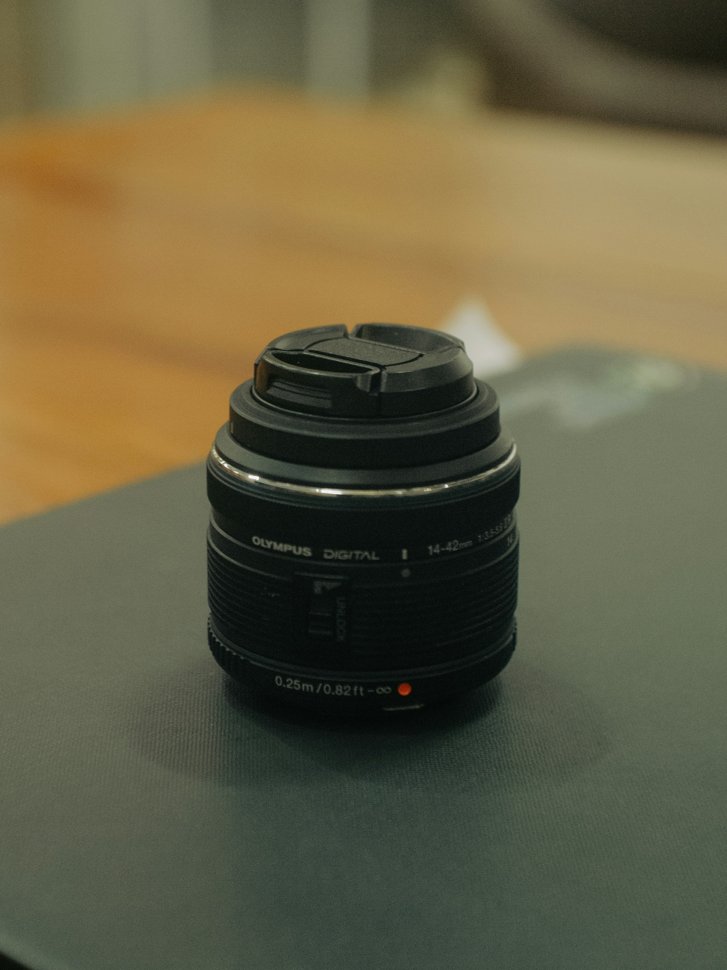 Compact Lens Cap: A Tiny Olympus rests on a dark mat