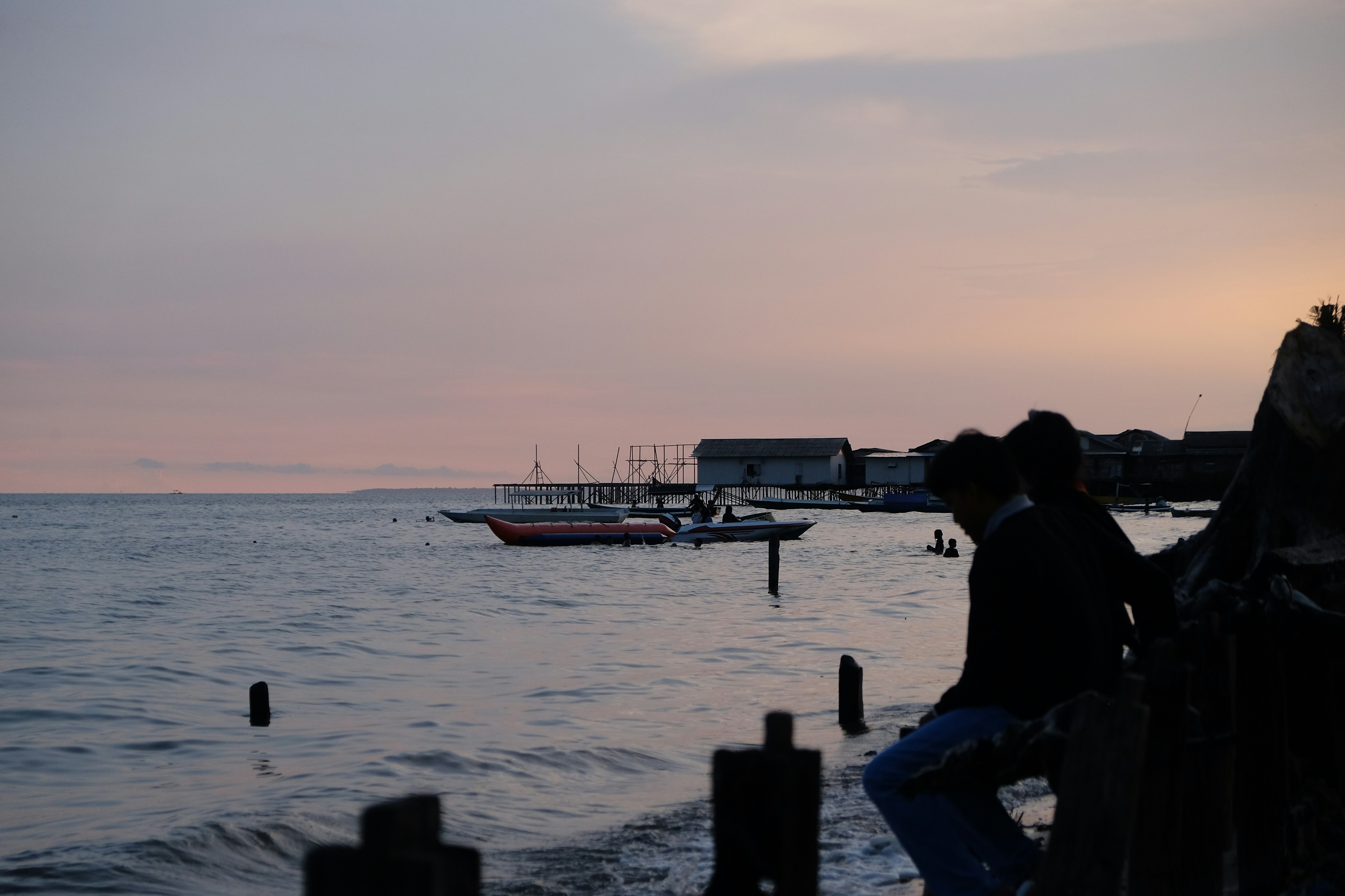 Evening Quiet at the Pier: A Distant Boat and Two Figures in Shadow