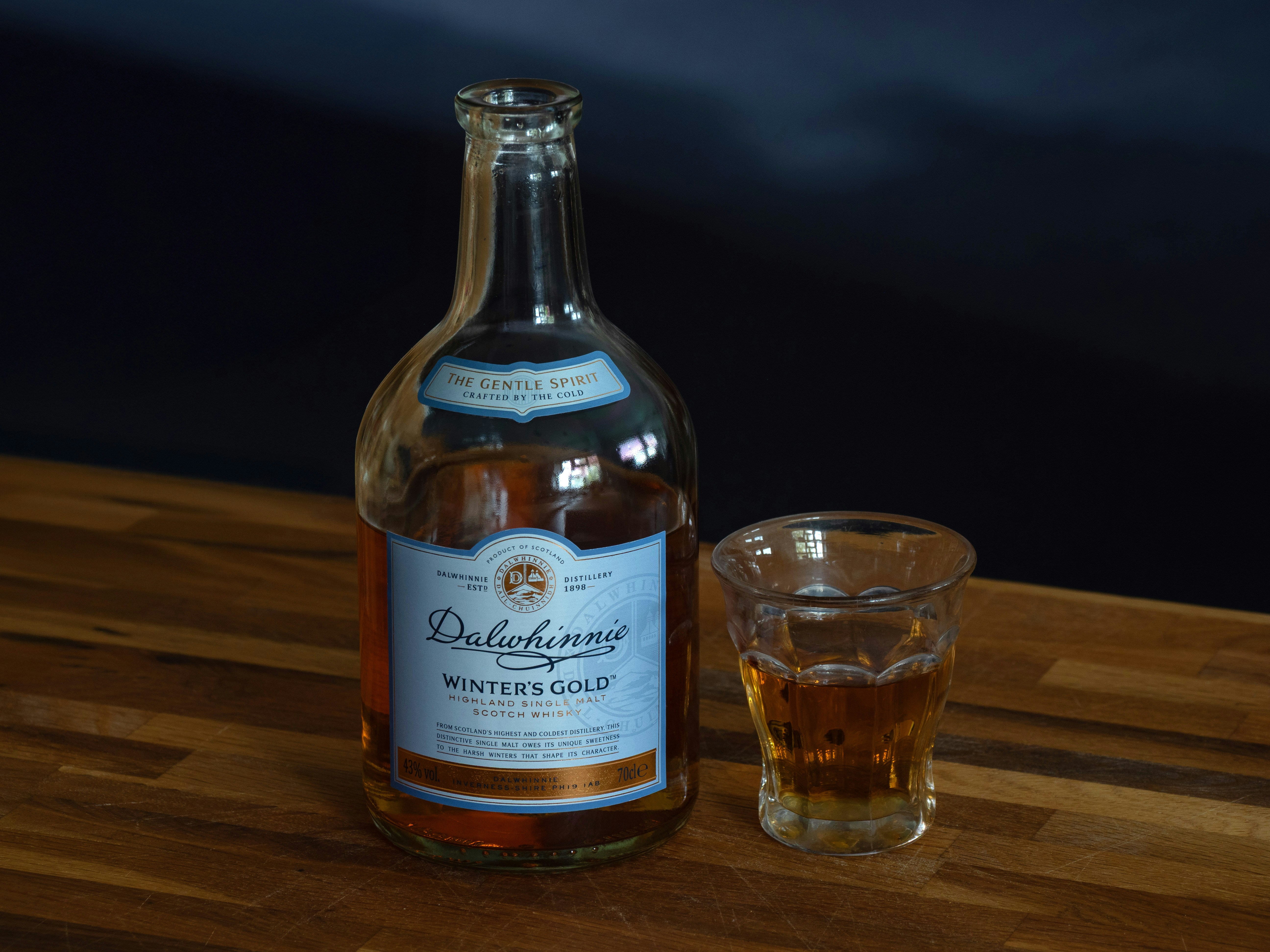 Winter’s Gold on the Barrel: Bourbon Bottle and Glass in Quiet Evening Light