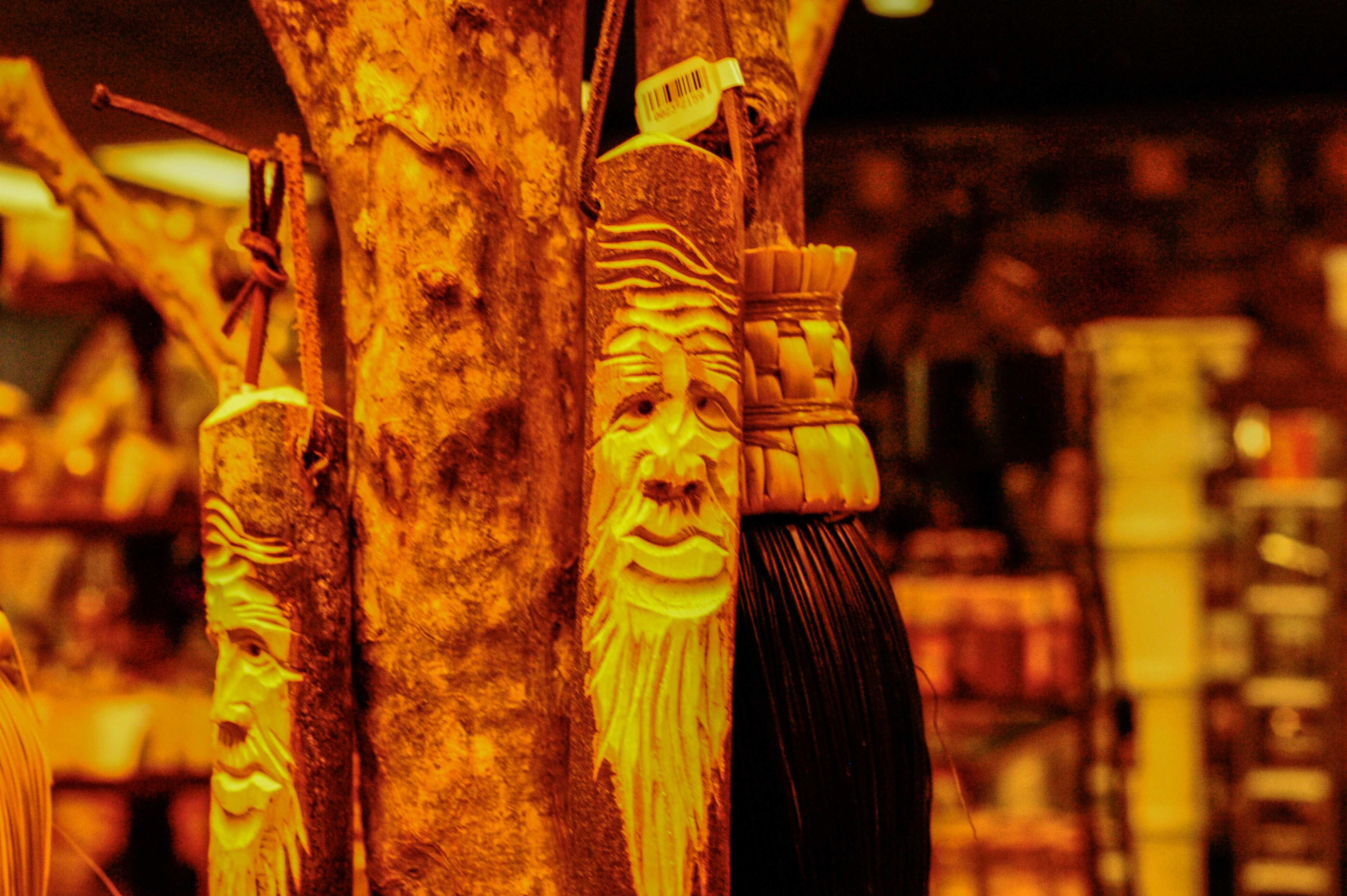 Carved Wooden Trolls Framing a Broom at a Busy Market