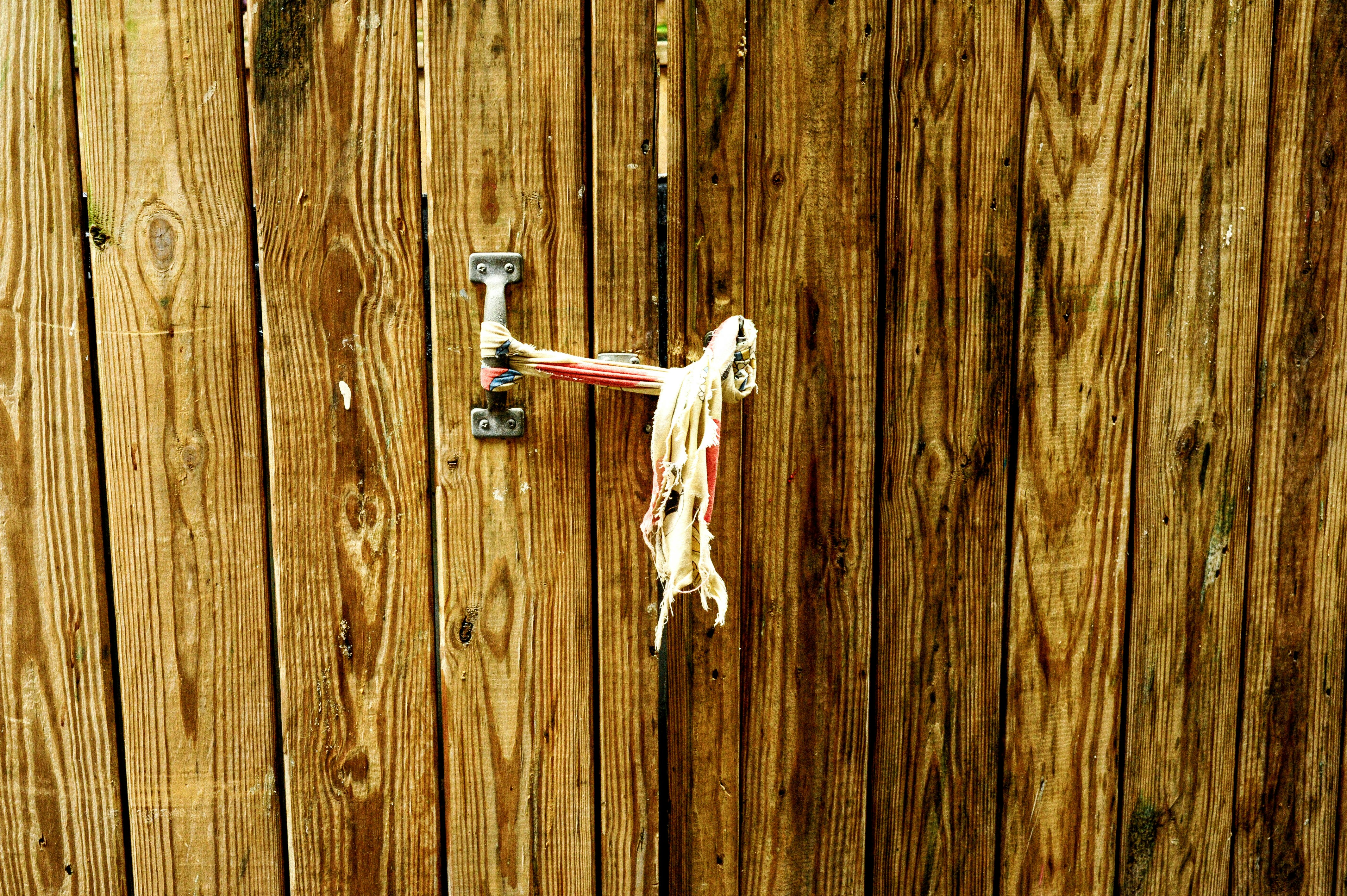Torn Banner: A Weathered Handle Clings to a Wooden Fence