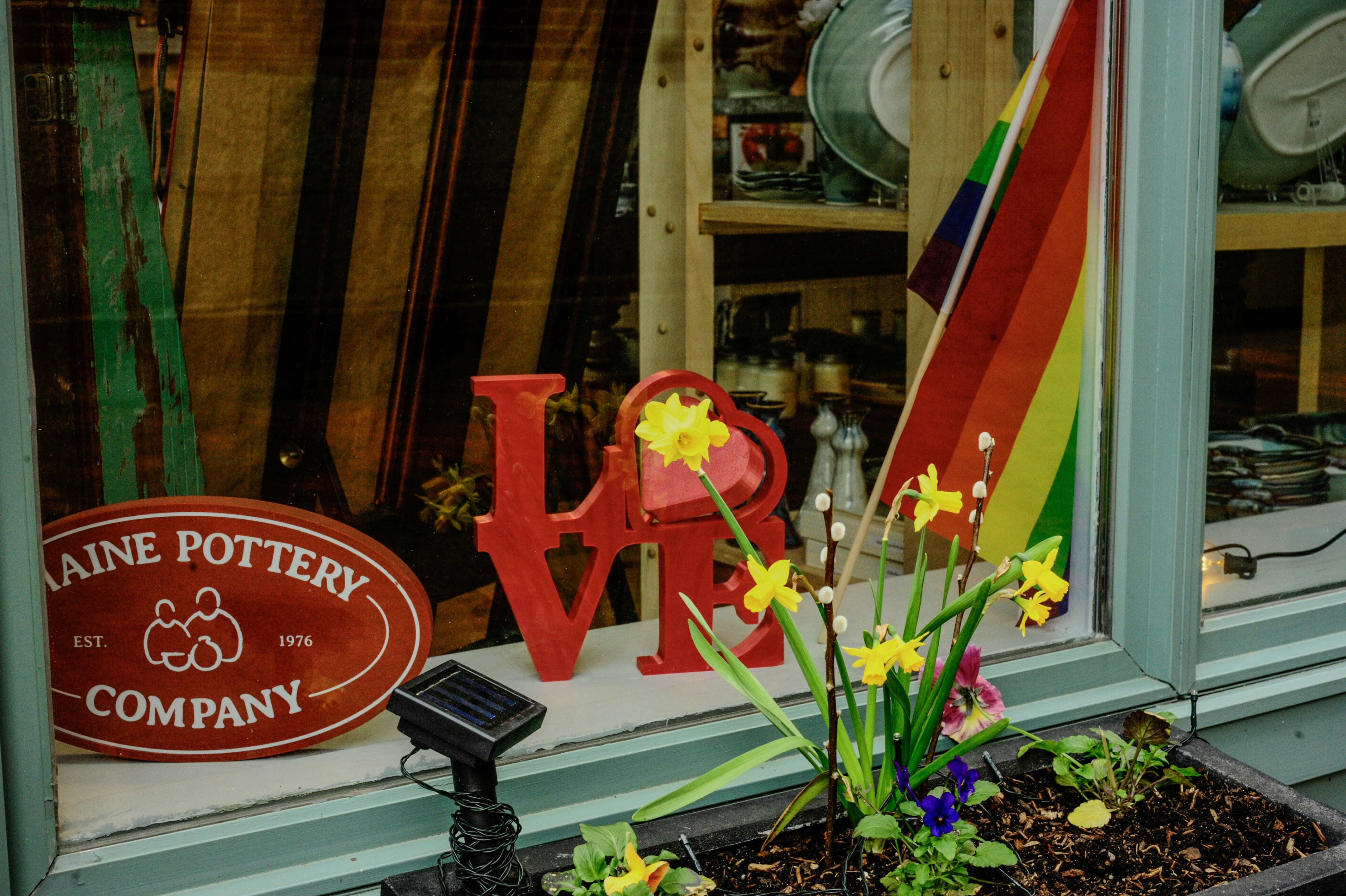 Colorful Pottery Shop Window with Bright Signage and Daffodils