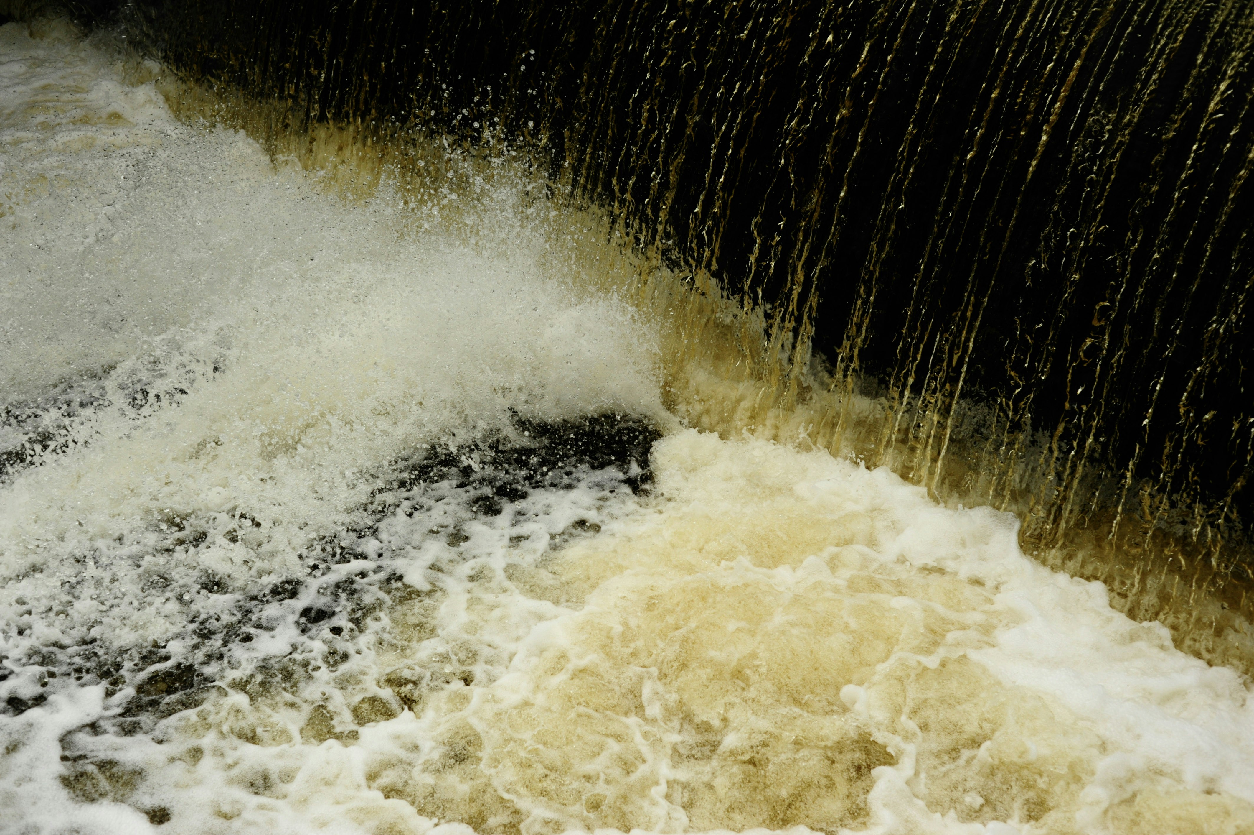 Whitewater Curtain: Aerial Rush Over Tan-edged Rapids