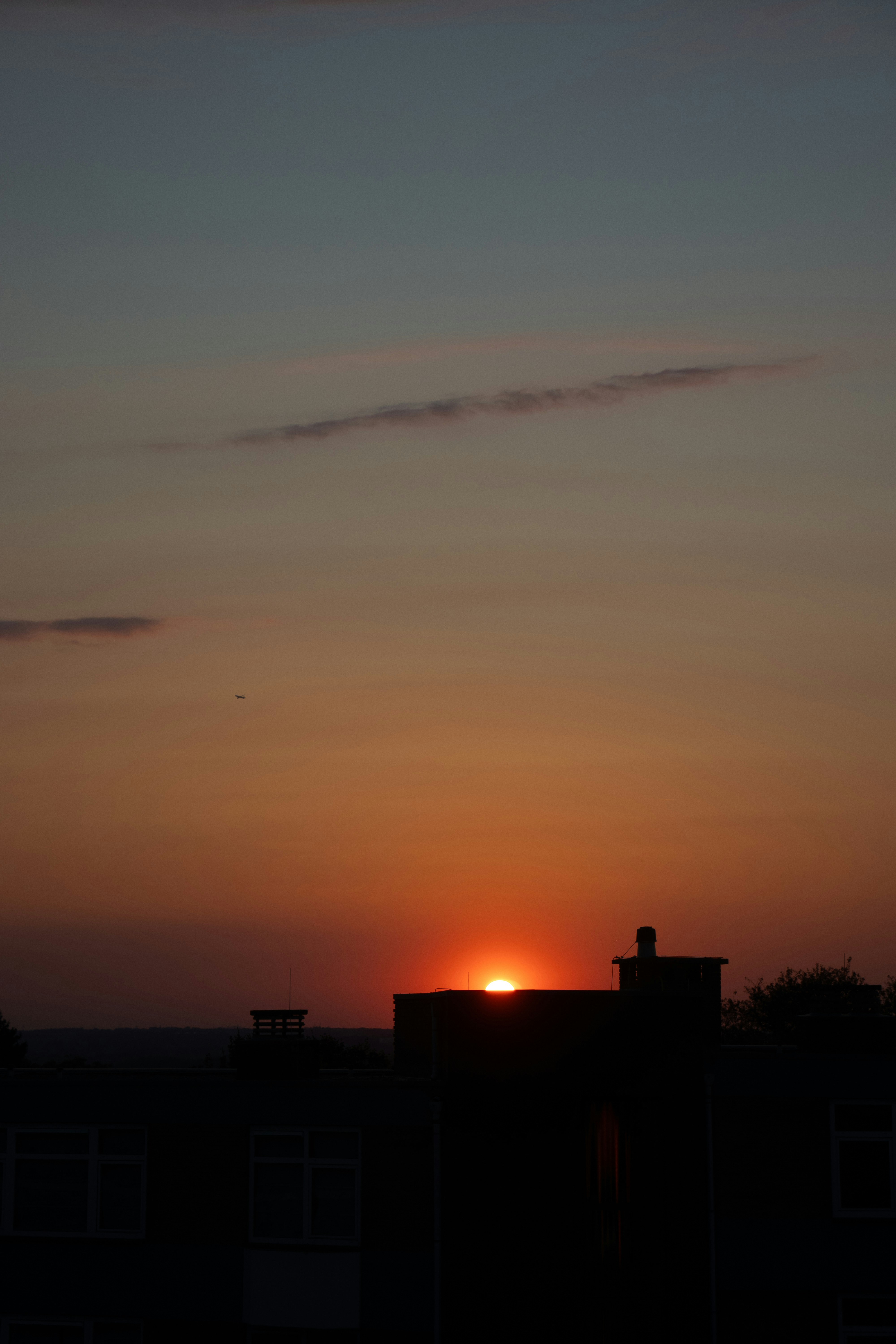 Sunset silhouette over a quiet rooftop horizon