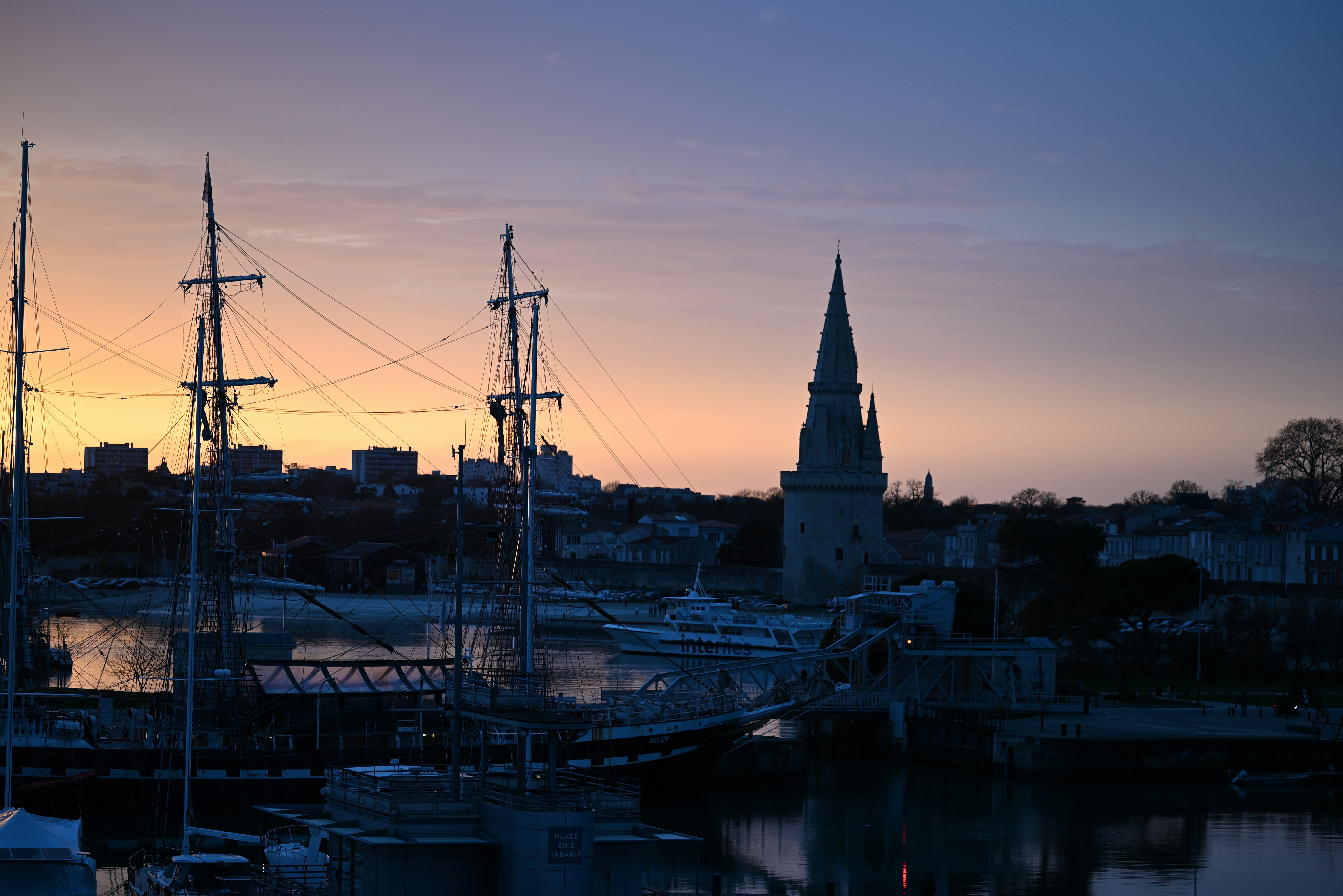 Dusk at the Harbor: Sails Silhouetted Against a Quiet Skyline
