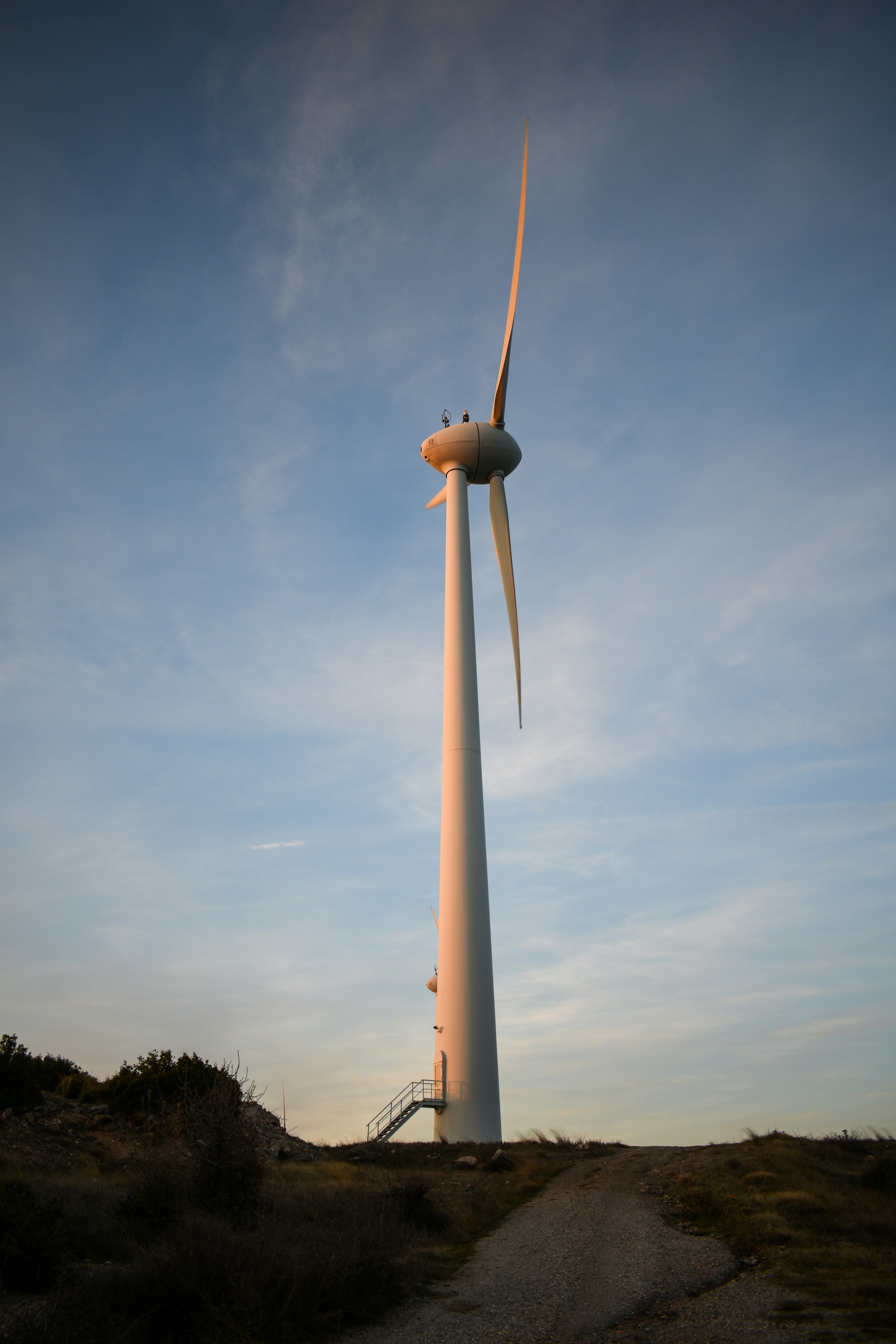 Evening Witness: A solitary wind turbine Standing Against a Wrinkled Sky