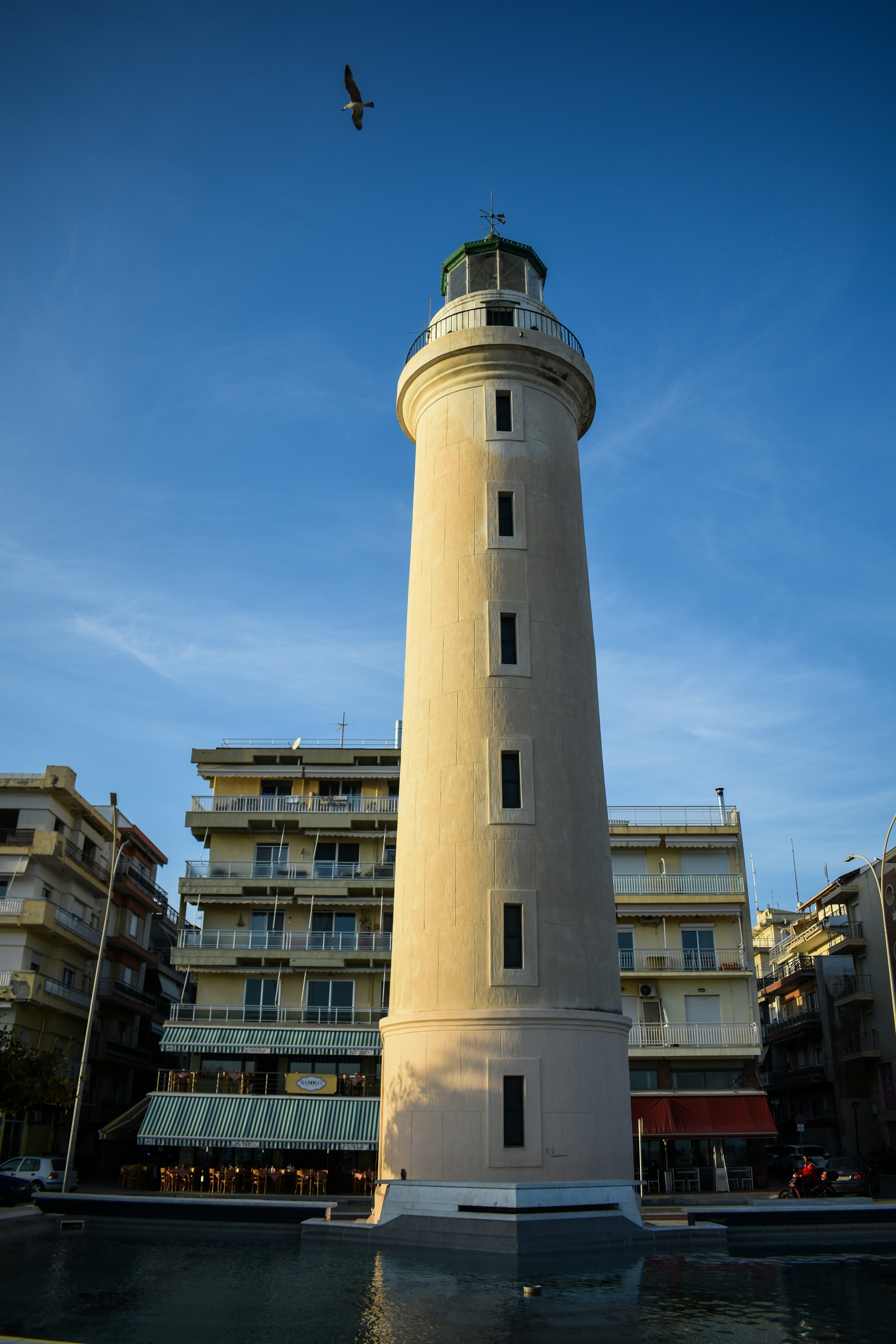 Beacon in the City: Tall Standalone Lighthouse Rising Over a Coastal Block