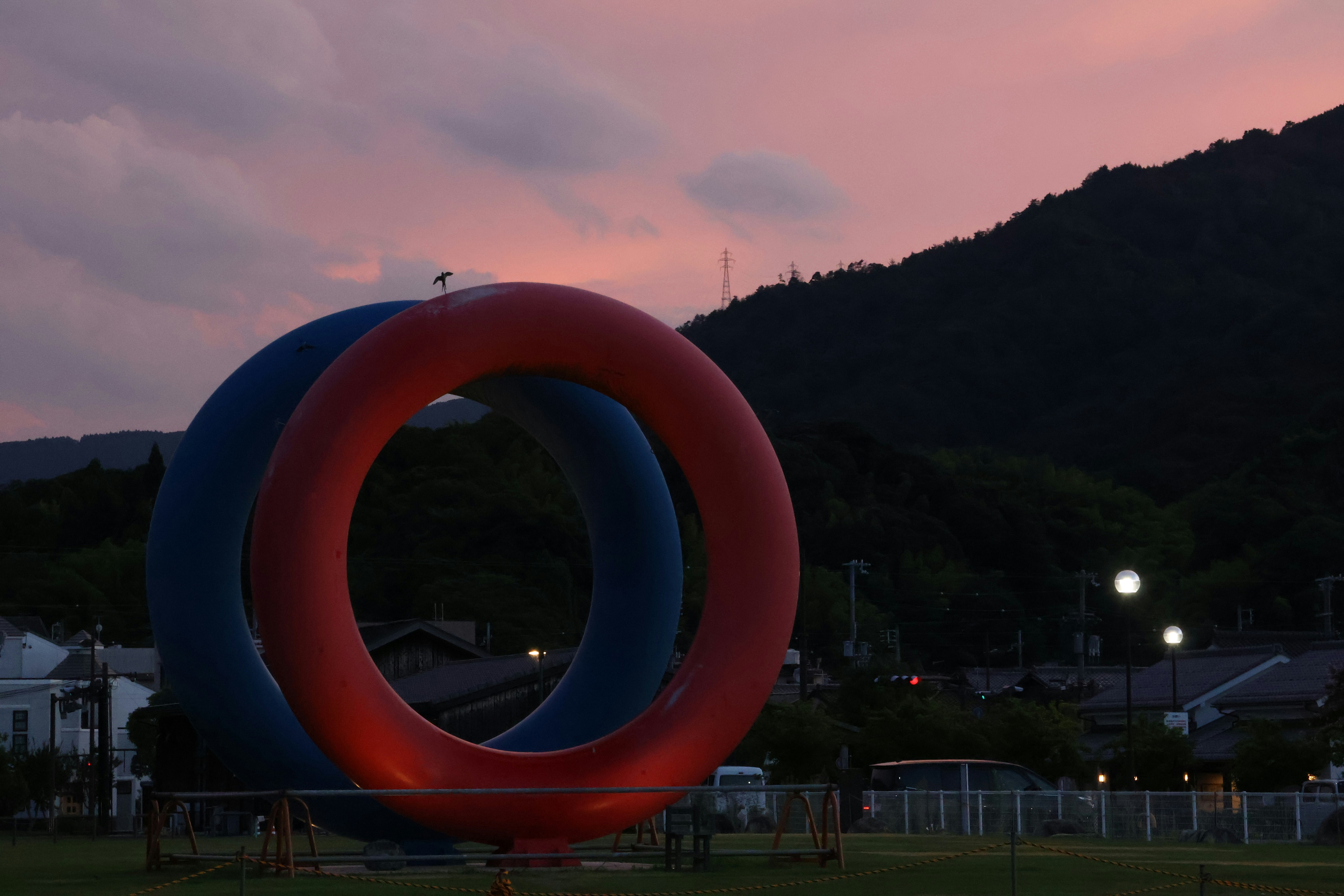 Orbits at Dusk: Red and Blue Rings Framing a Quiet Town