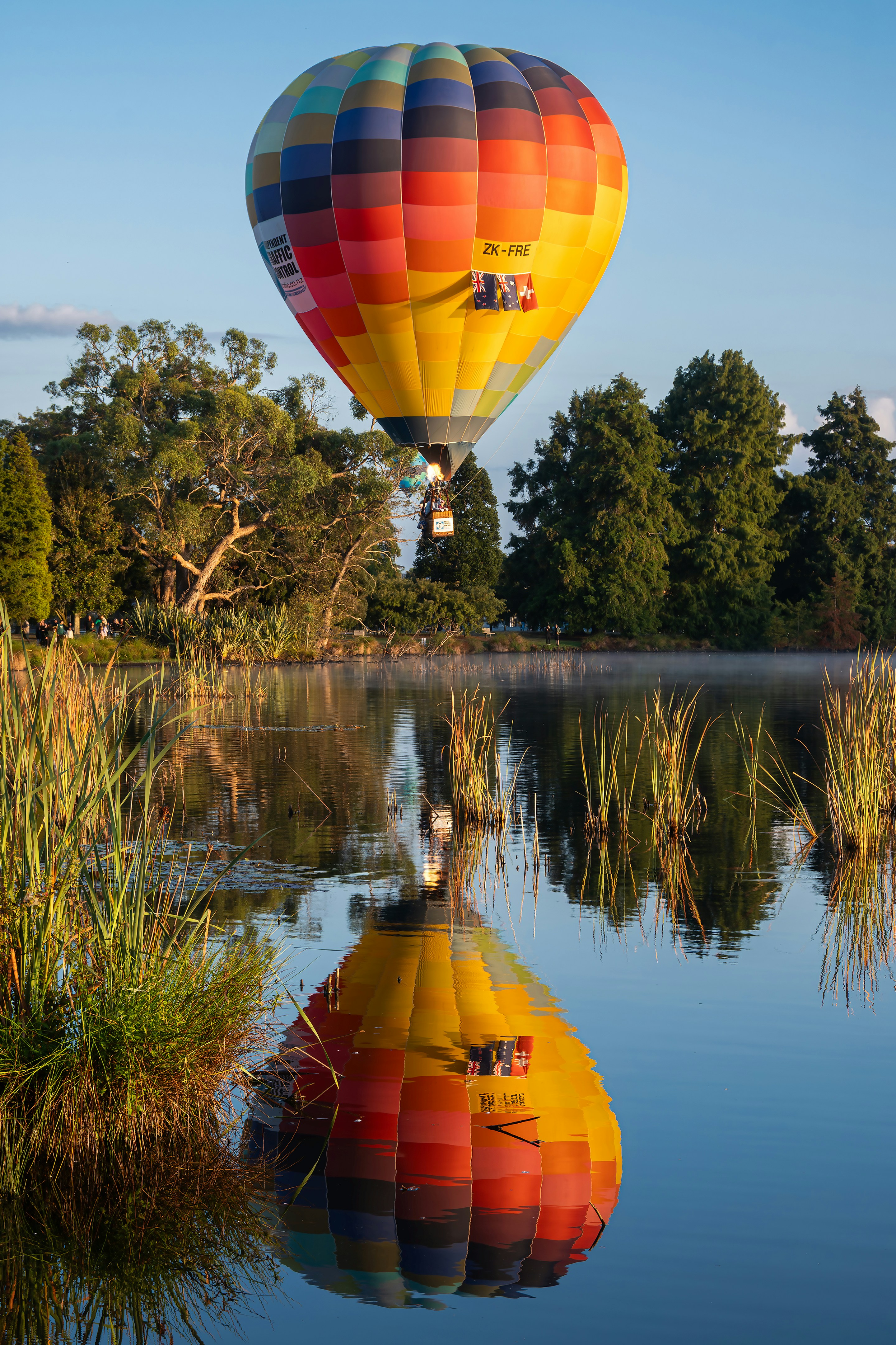 Floating Prism: A Crimson-Gold Balloon Quietly Rises Over a Mirror-Still Marsh
