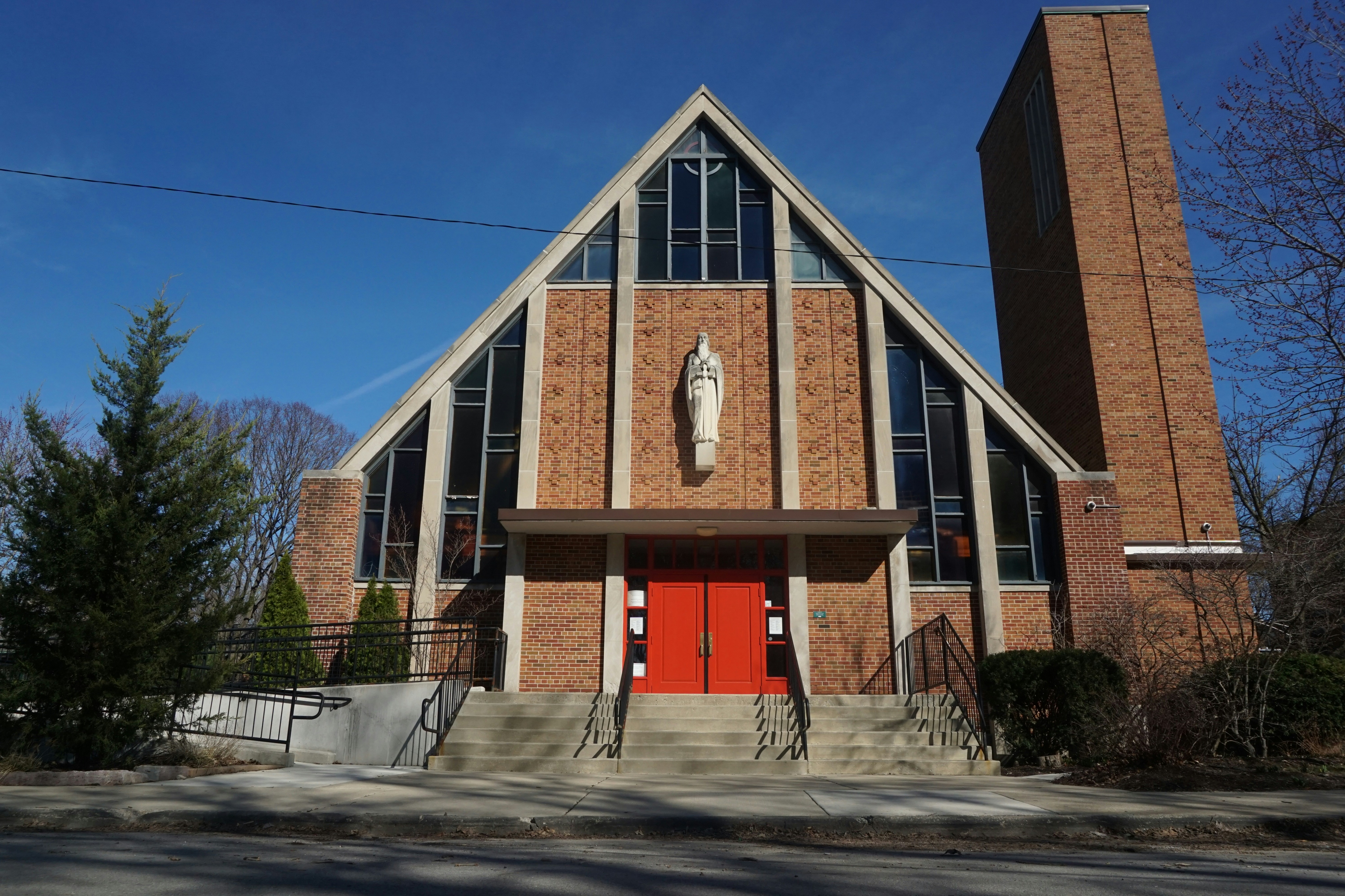 Red Doors, Steepled Silence: A Church with Brick Facade and Triangular Glass