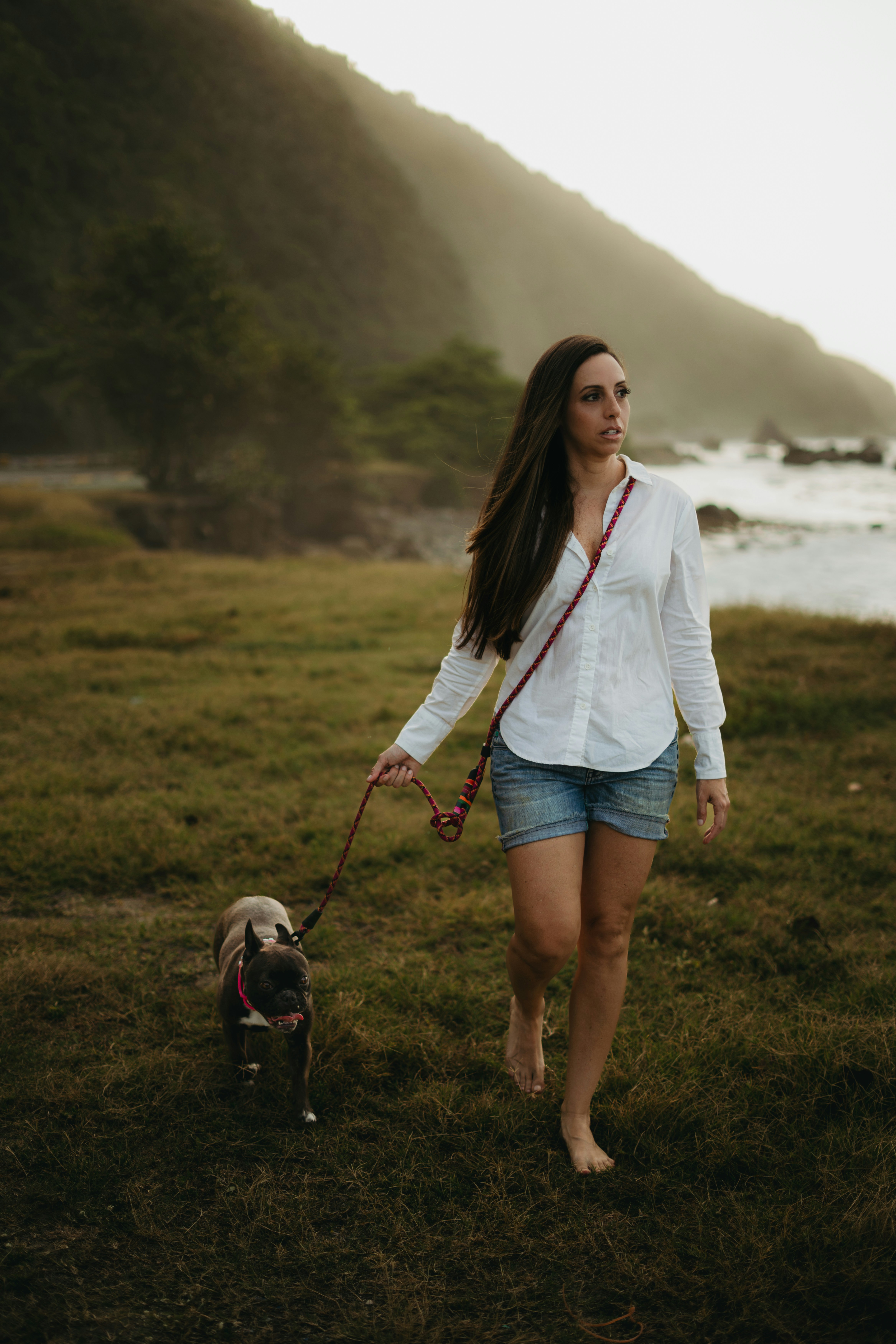 Coastal Walk with a Leashed Contrast: Woman and Her Small Dog