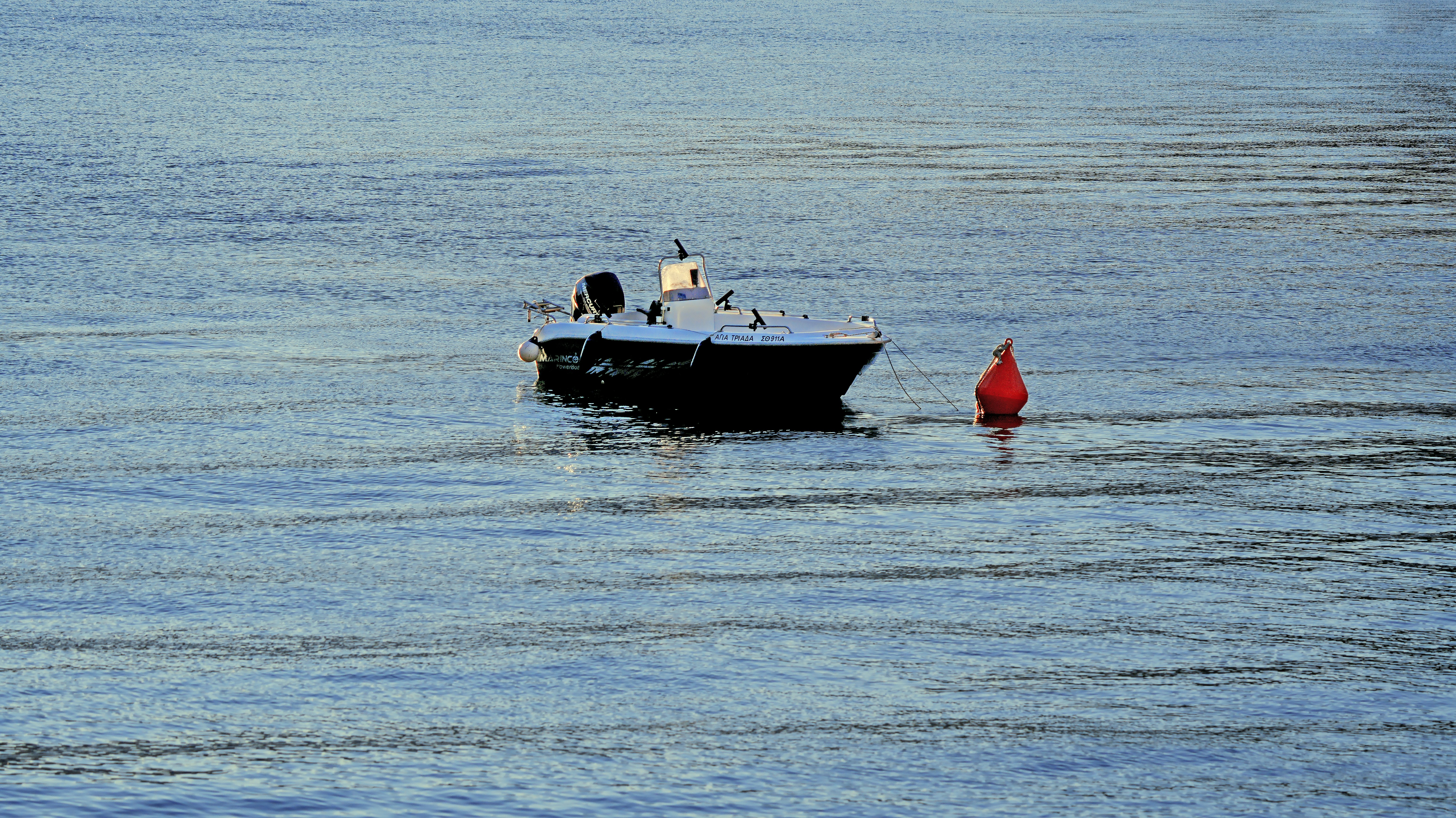 Boat Drifting on Quiet Blue Waters with Red Buoy