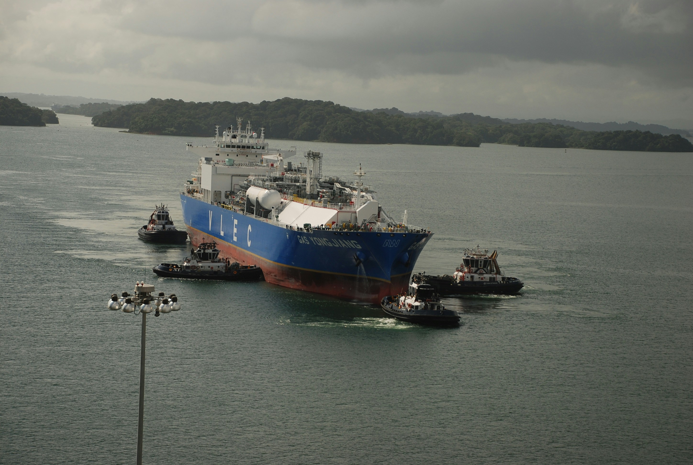Blue-and-White Bulk Carrier Guided by Tugs in Open Water