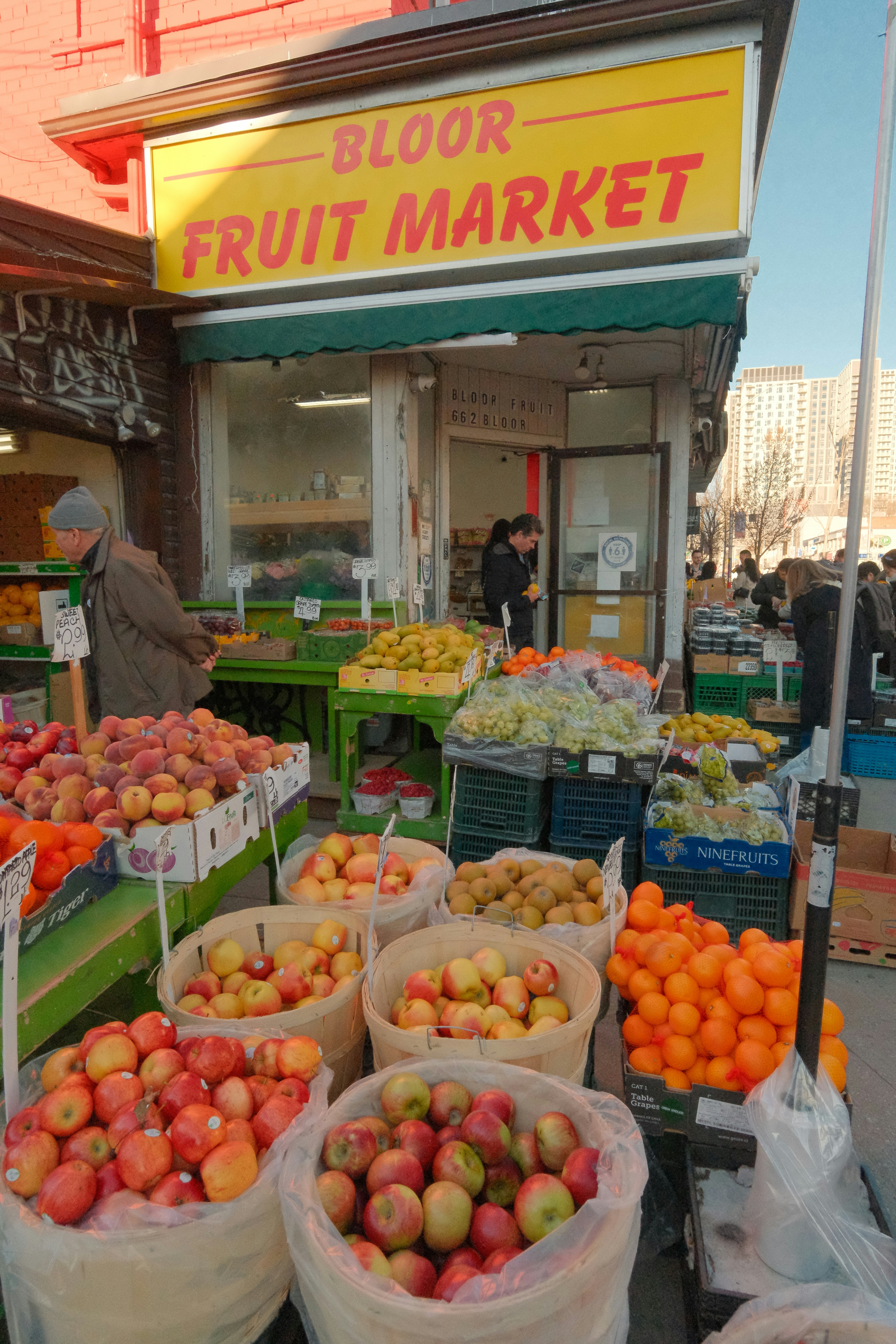 Bright Harvest: A Bustling Fruit Market Under a Red-Accent Sign