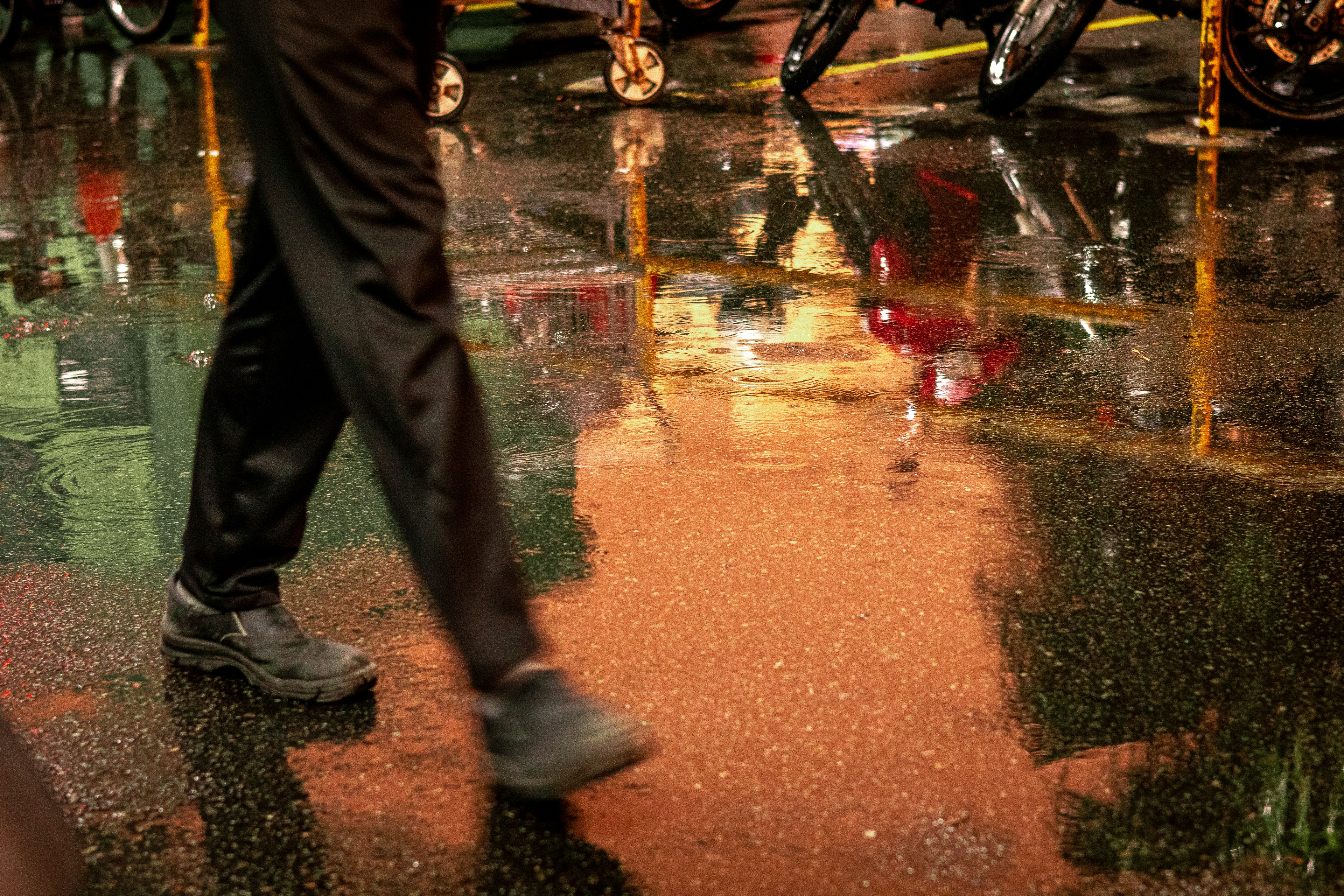 Late Night Pedestrian Steps Through Rain-Soaked Neon