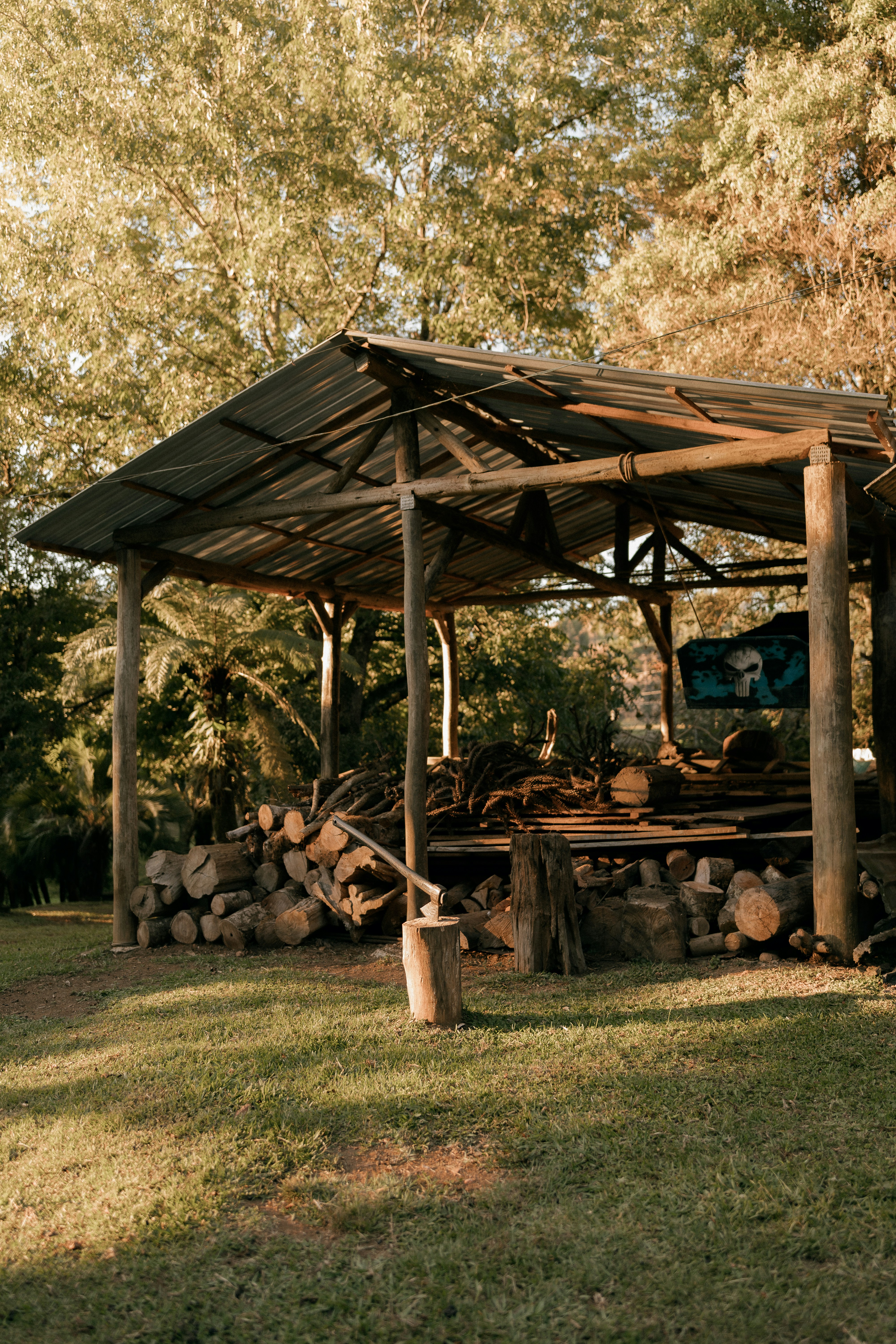 Sunlit Lumber Shelter: A Quiet Woodpile Under a Rustic Roof