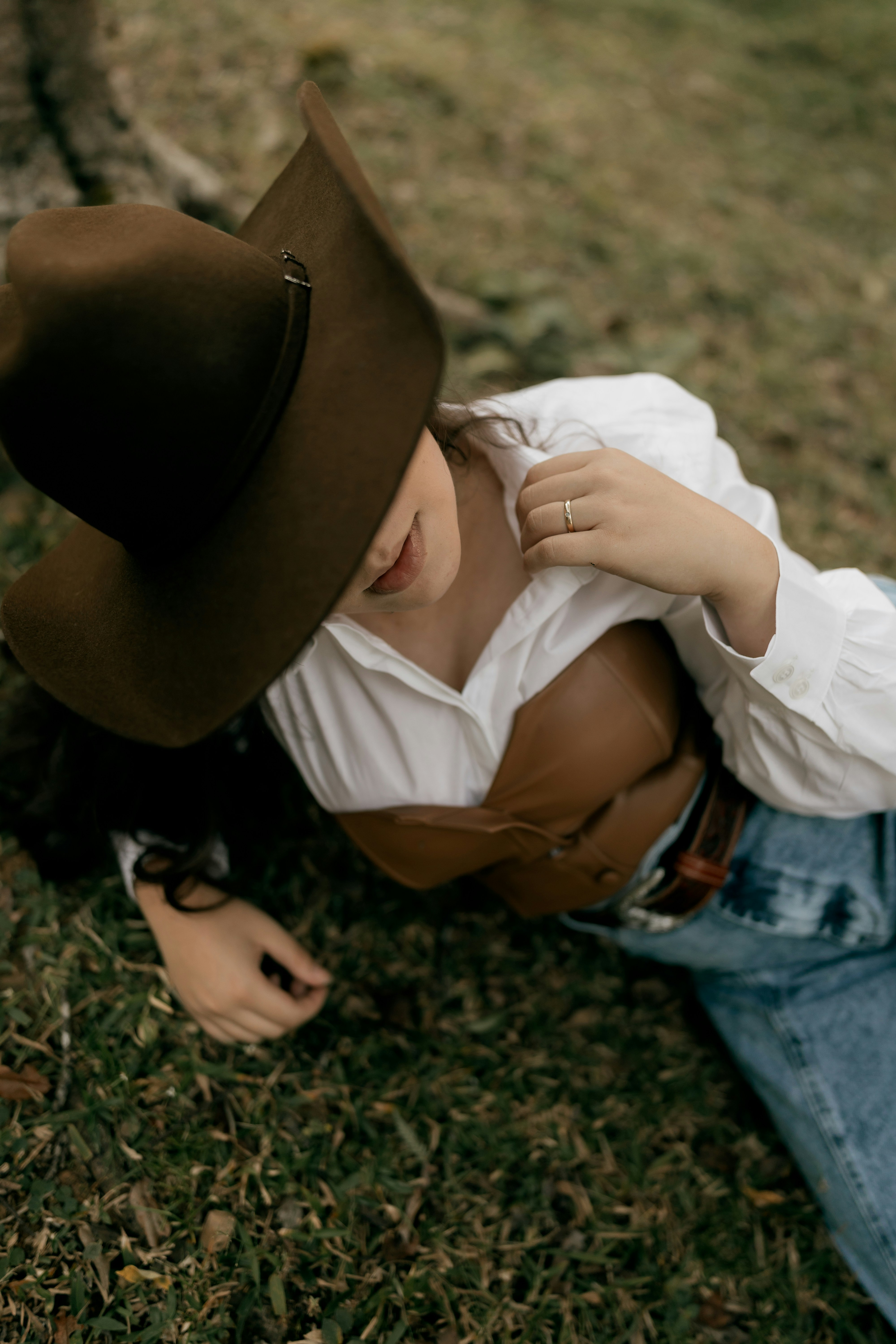 Portrait in a Quiet Meadow: A Woman in Hat and Western Attire Resting on the Grass