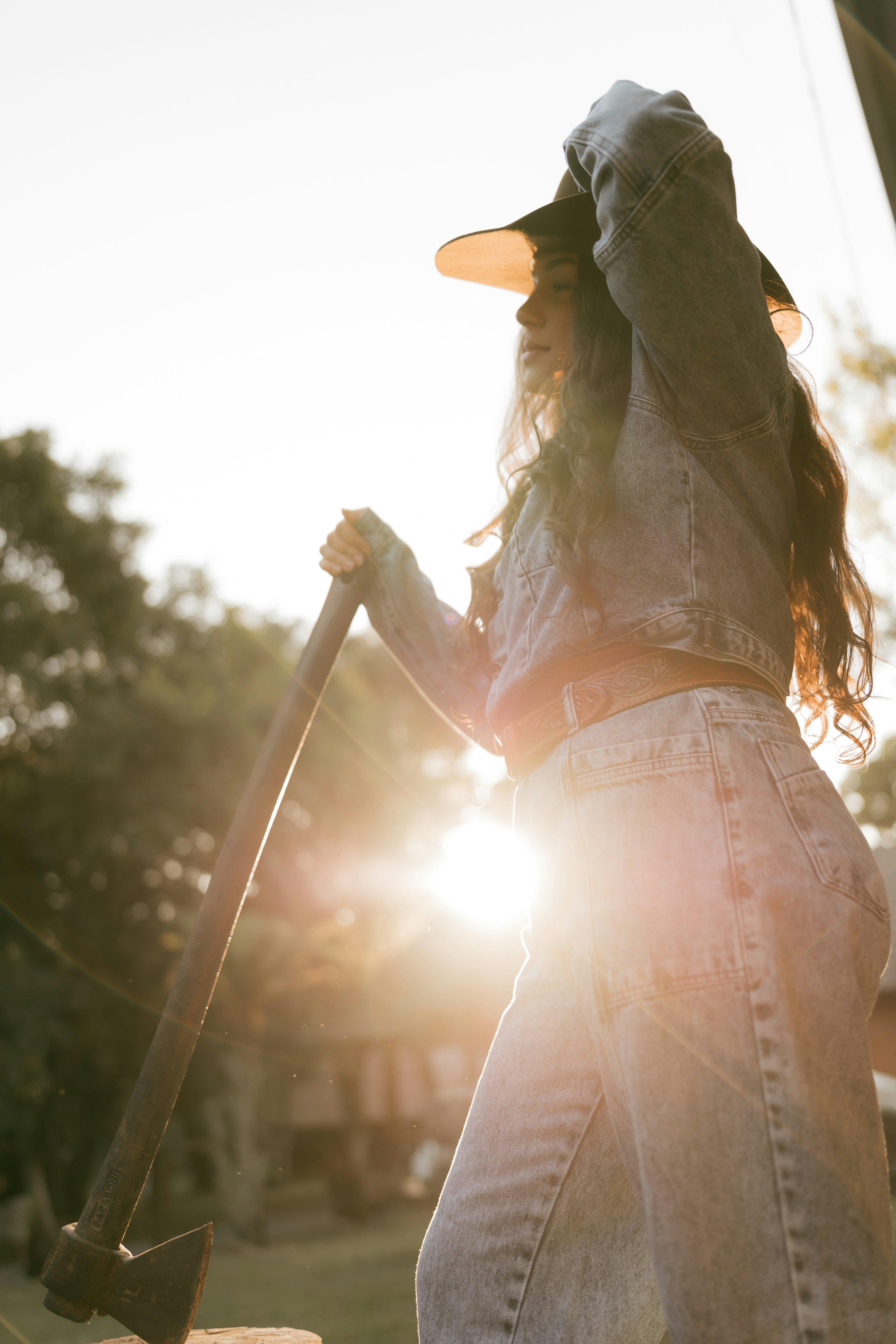 Sunlit silhouette: a denim-clad figure with a tool against the golden hour glow
