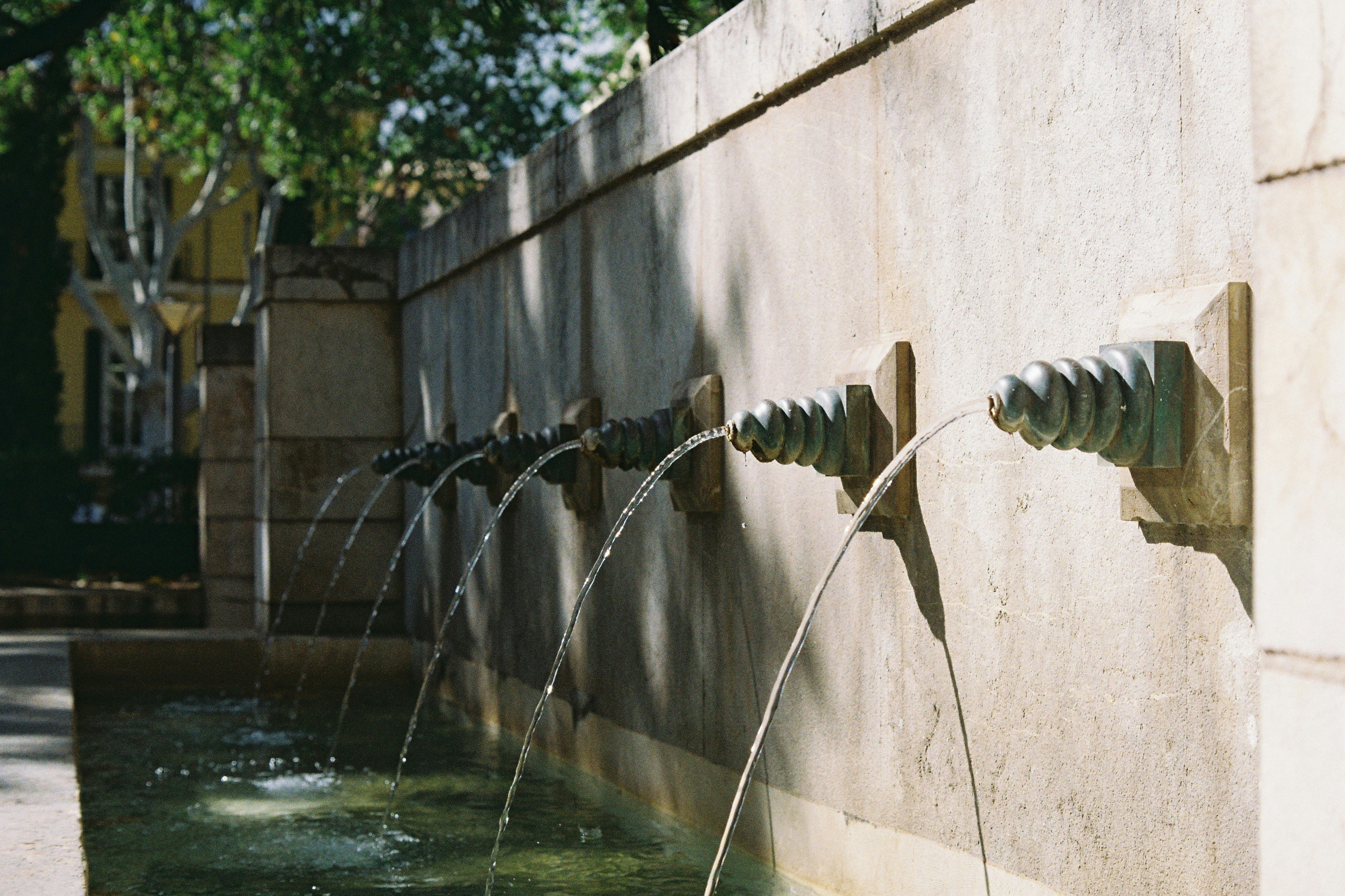 Evening Cascade: Water Arches Along a Quiet Wall