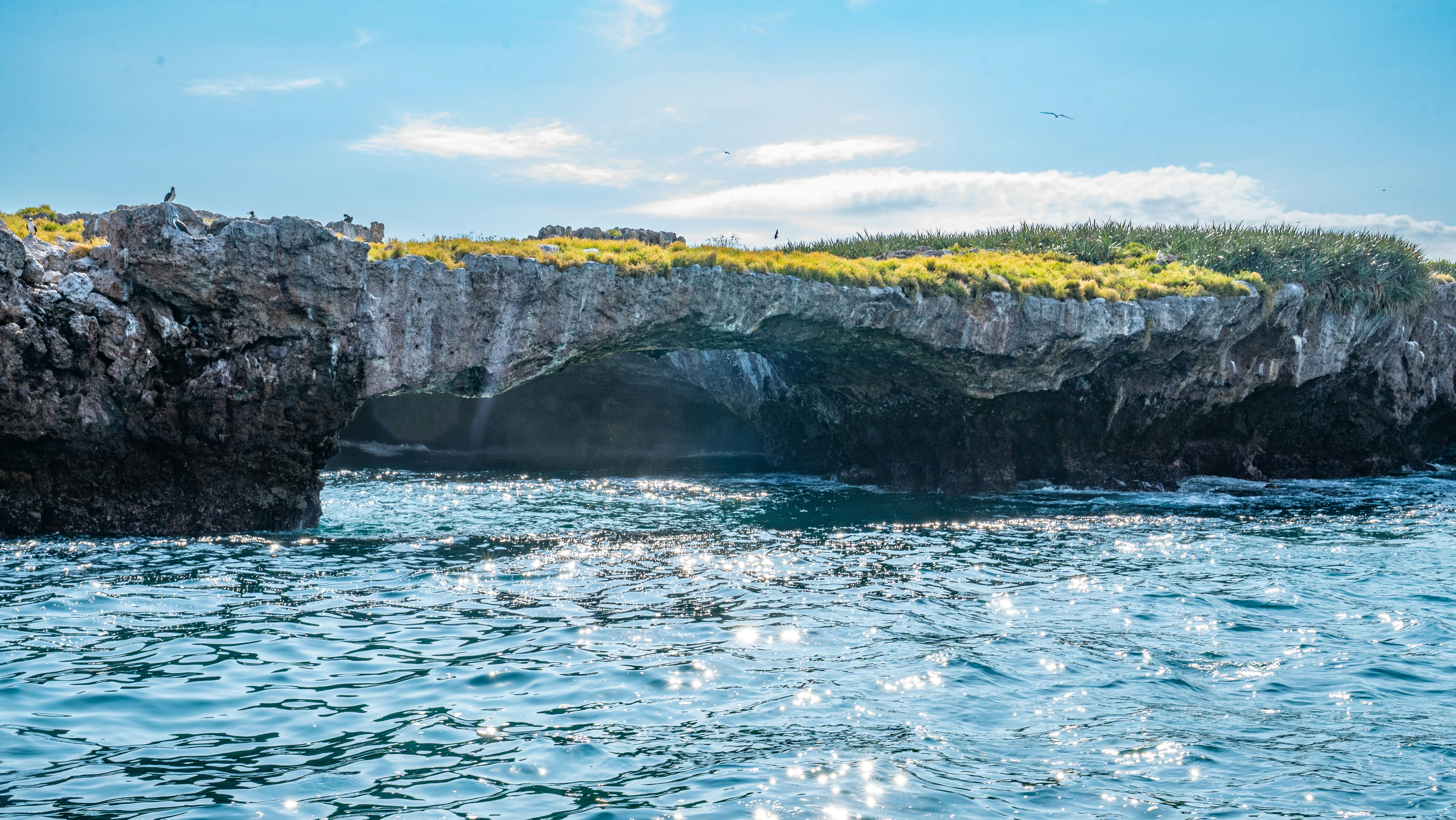 Sunlit Arch and Azure Waves: Cliffside Coastline at Dusk