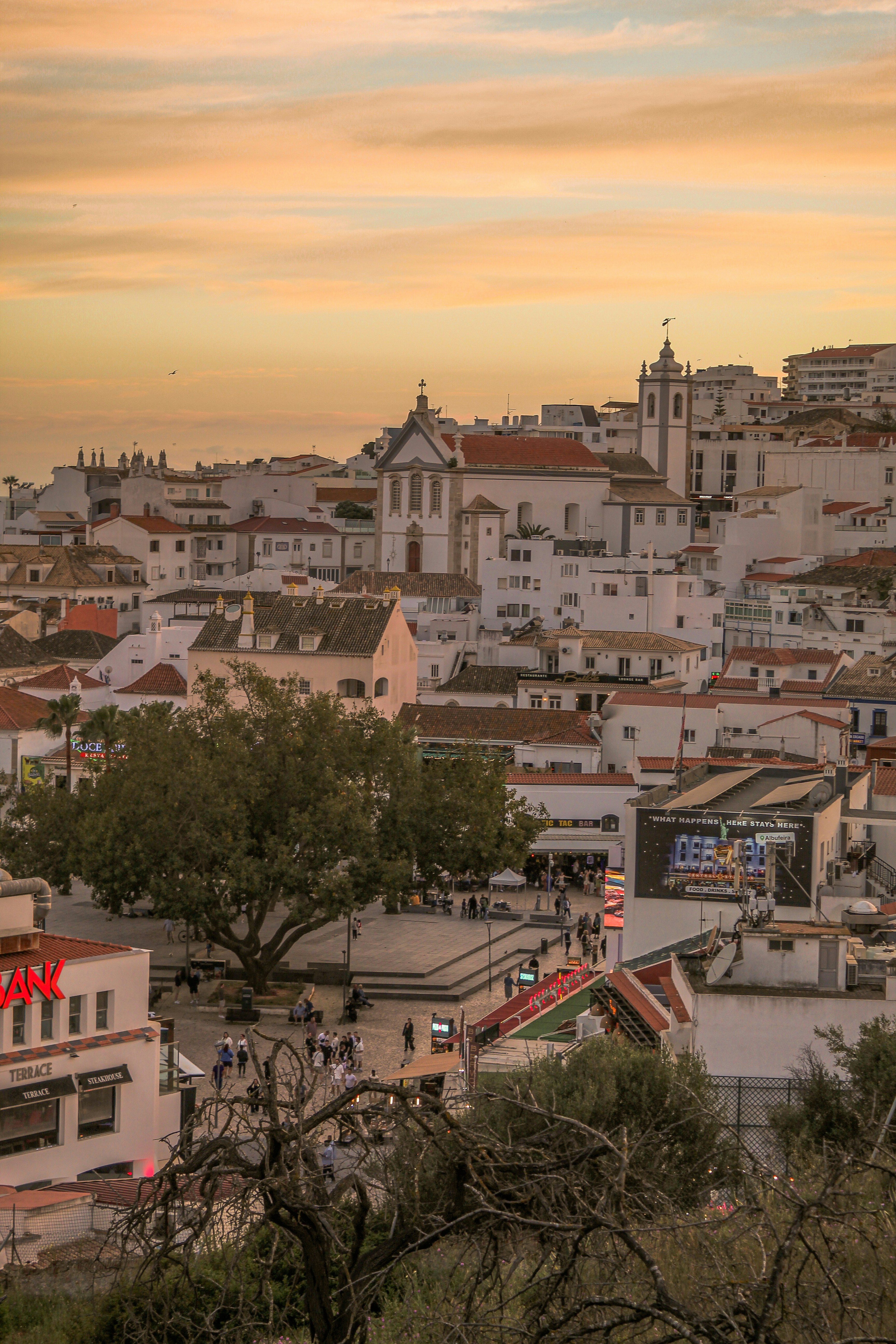 Sunset over a tiled hillside town with a lively square