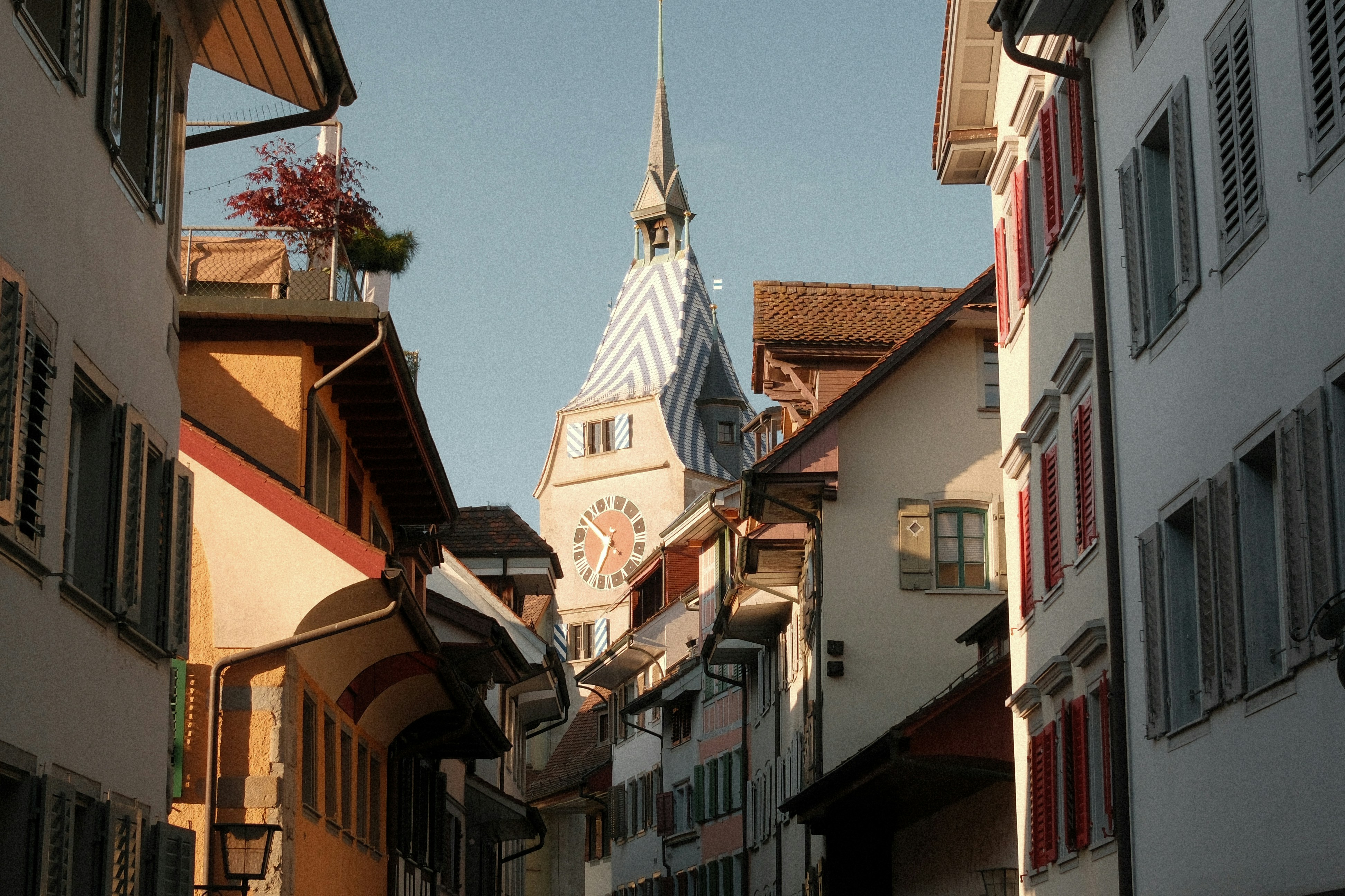 Clocktower Corridor: A Sunlit Alpine Street Between Gabled Facades