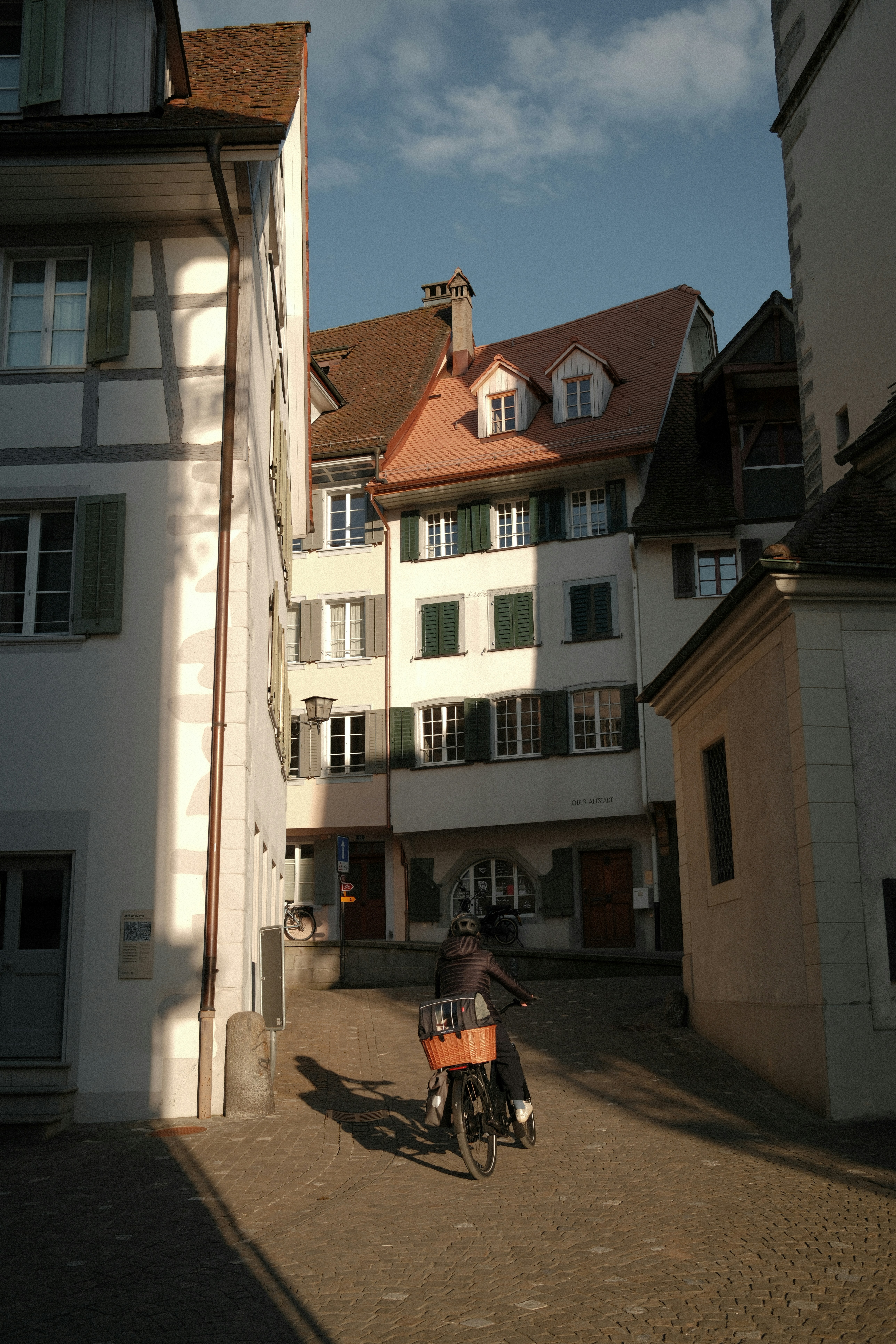 Cobbled Lane with Cyclist Toward a Sunlit Quarter