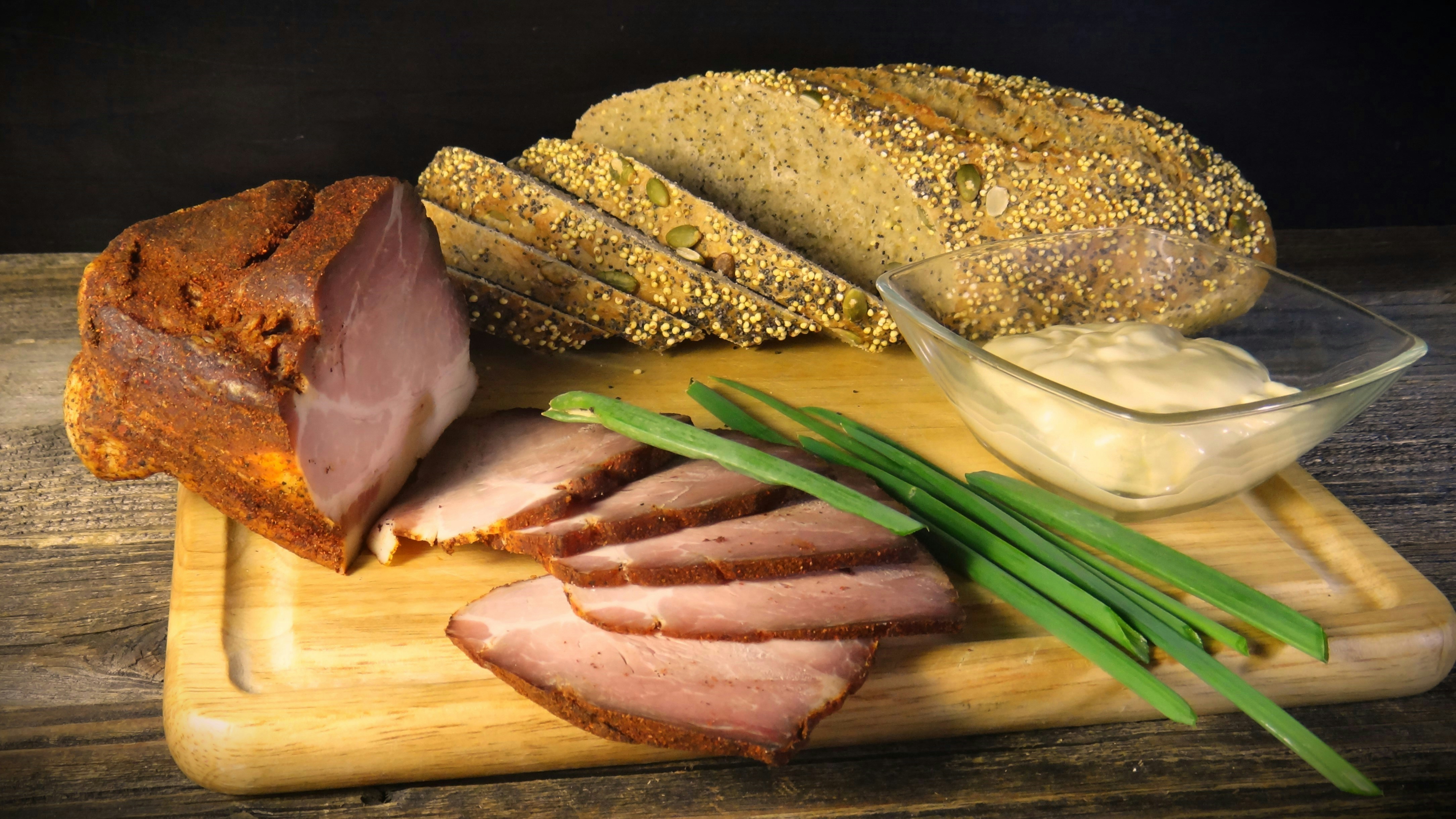 Heritage loaf and sliced ham on a rustic board