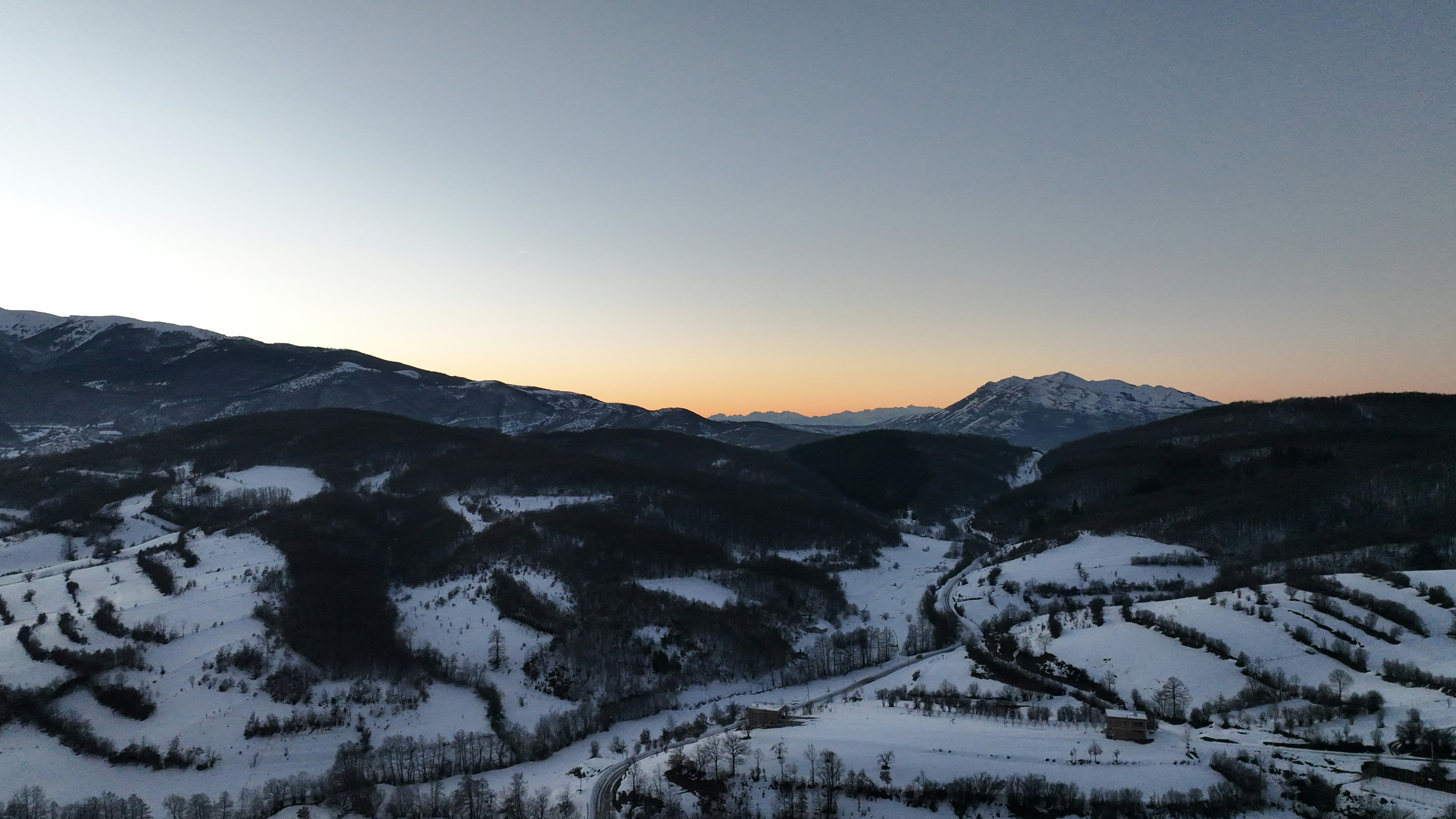 Winter Valley at Dusk: Snow-Covered Ridges Under a Quiet Sky