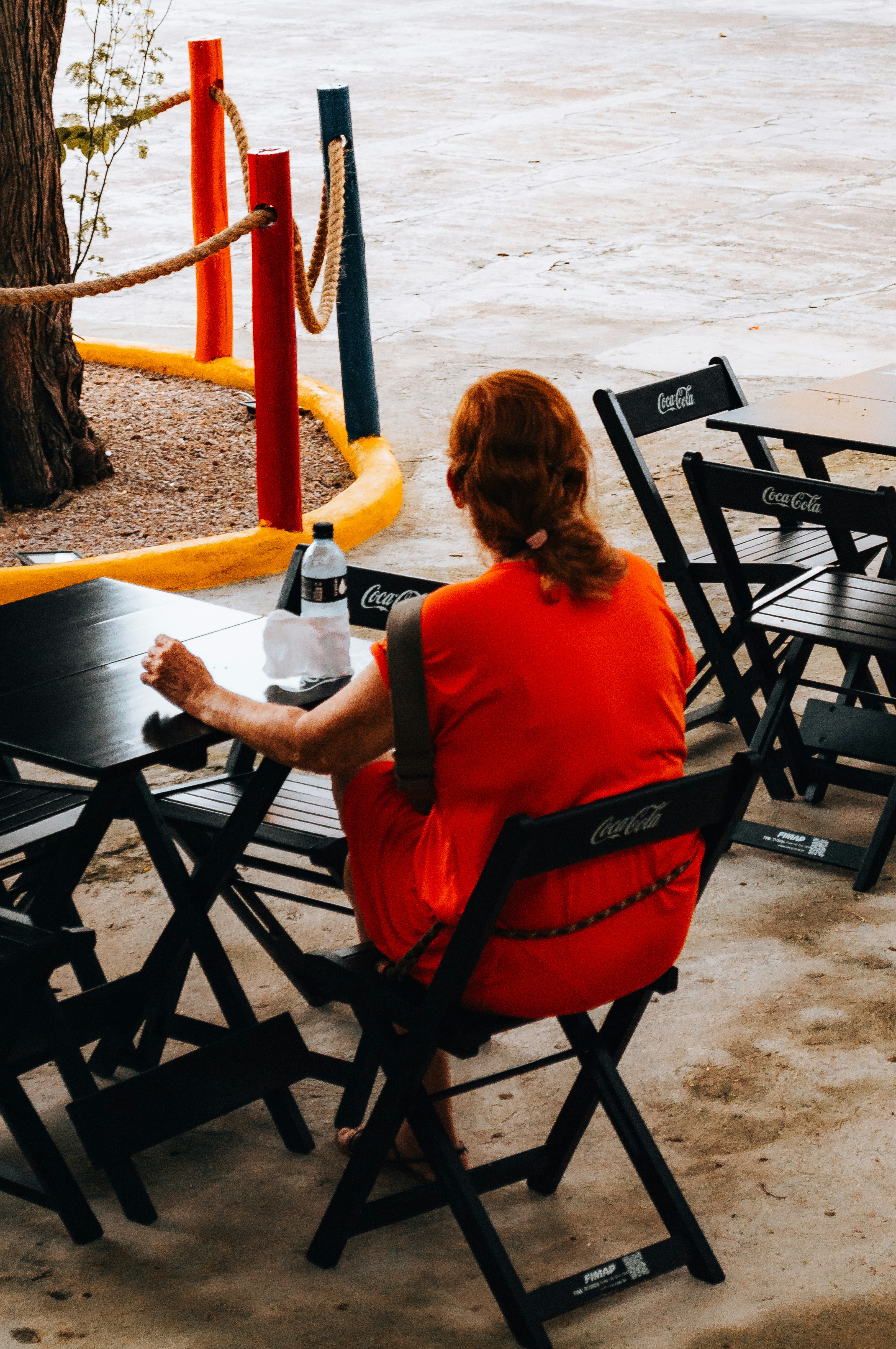 Red-clad silhouette at the café terrace under summer shade