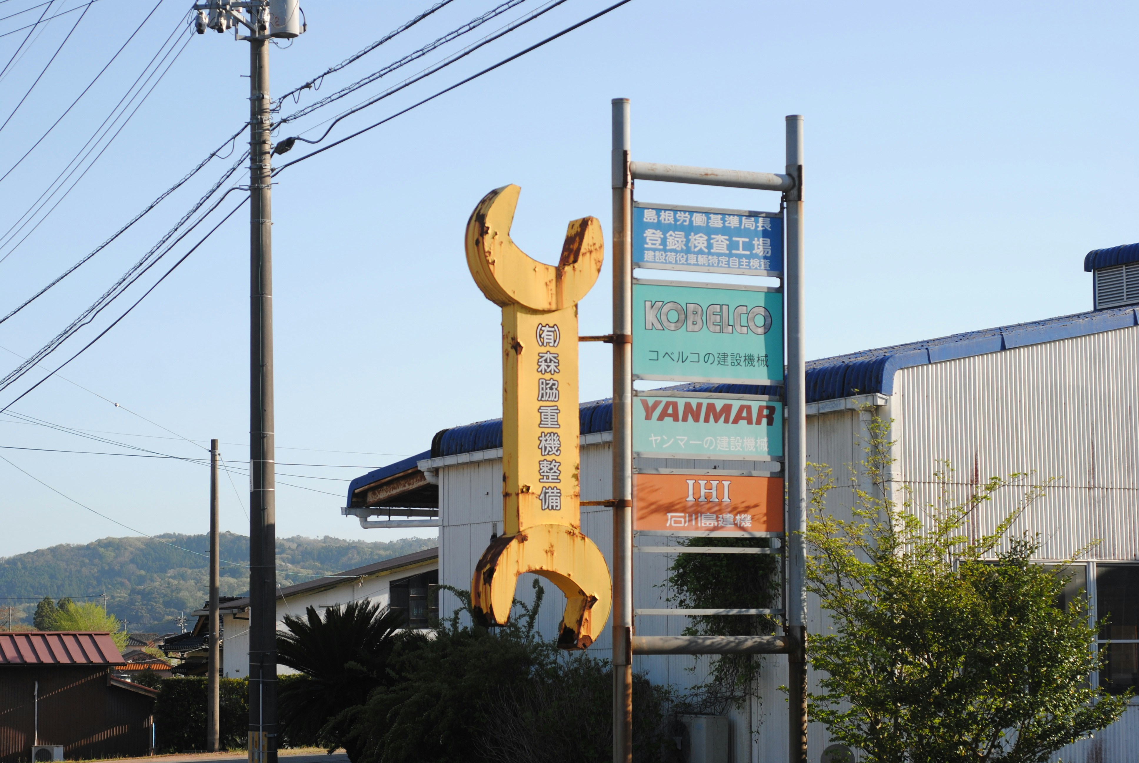 Industrial Signpost and Wrench Monument Rising Above a Sunny Street