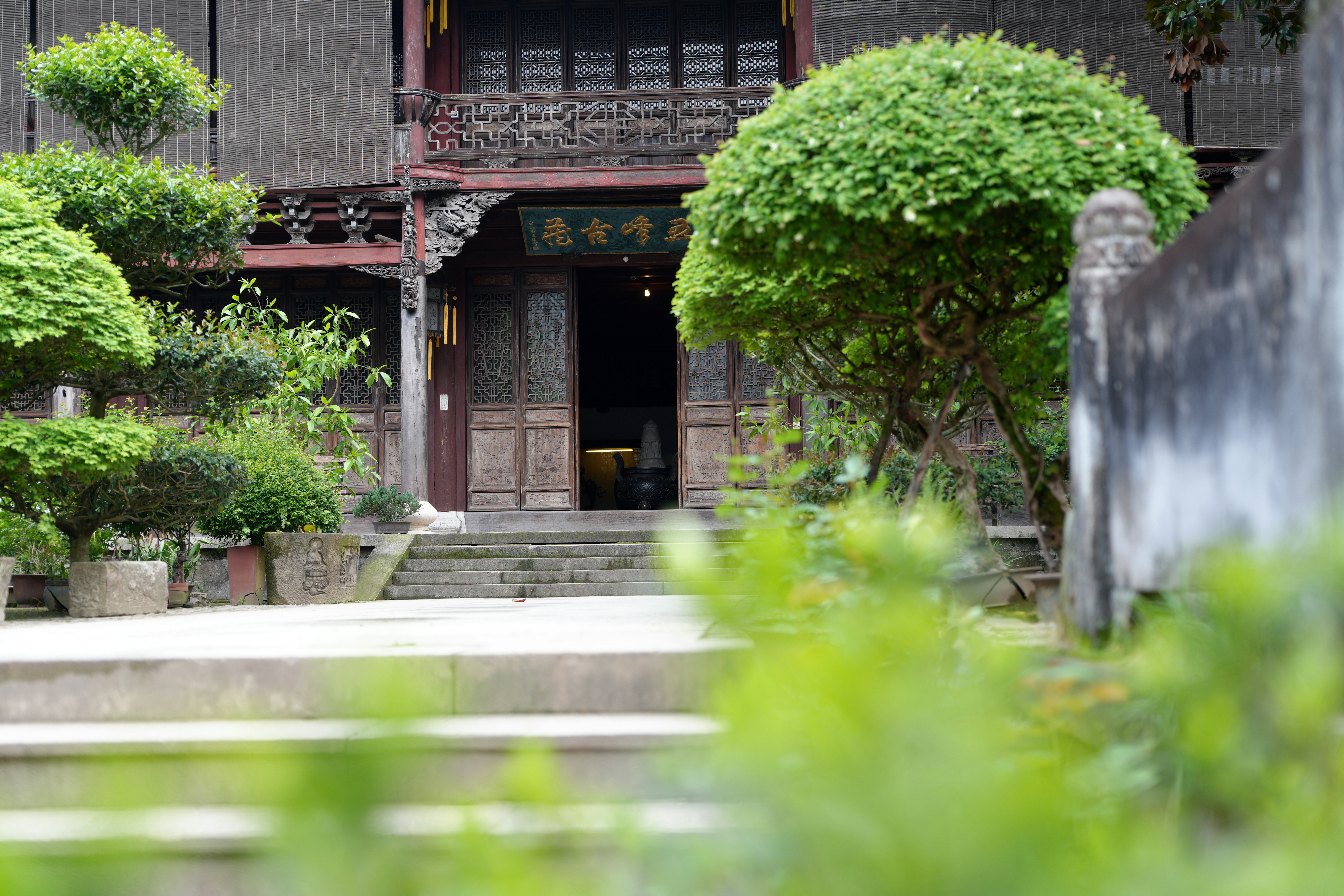 Entryway of Quiet Shrine: Carved Wood and Greenery Framing a Timeless Threshold
