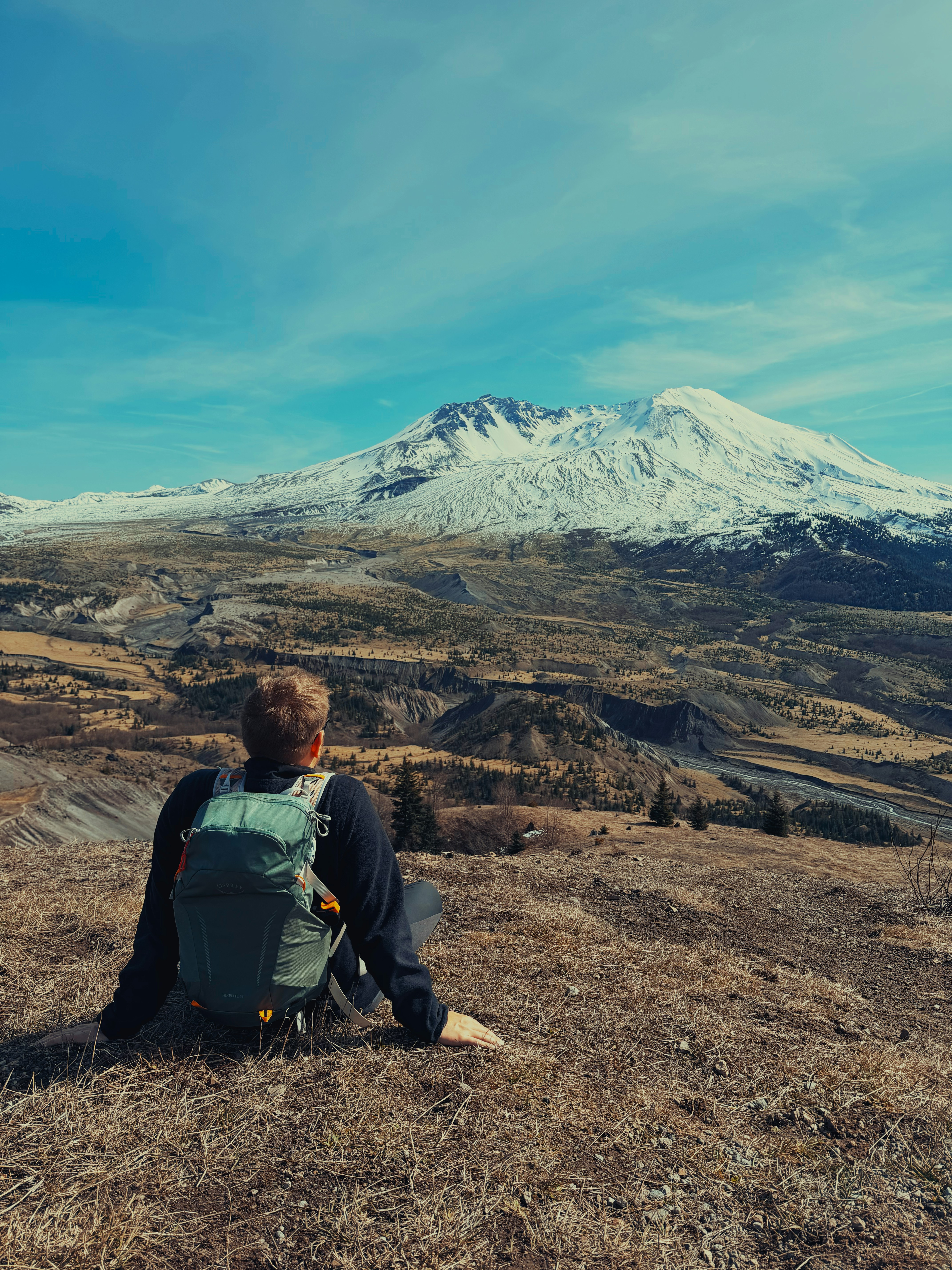Hiker on a Distant Rim Beneath Snow-Capped Peaks